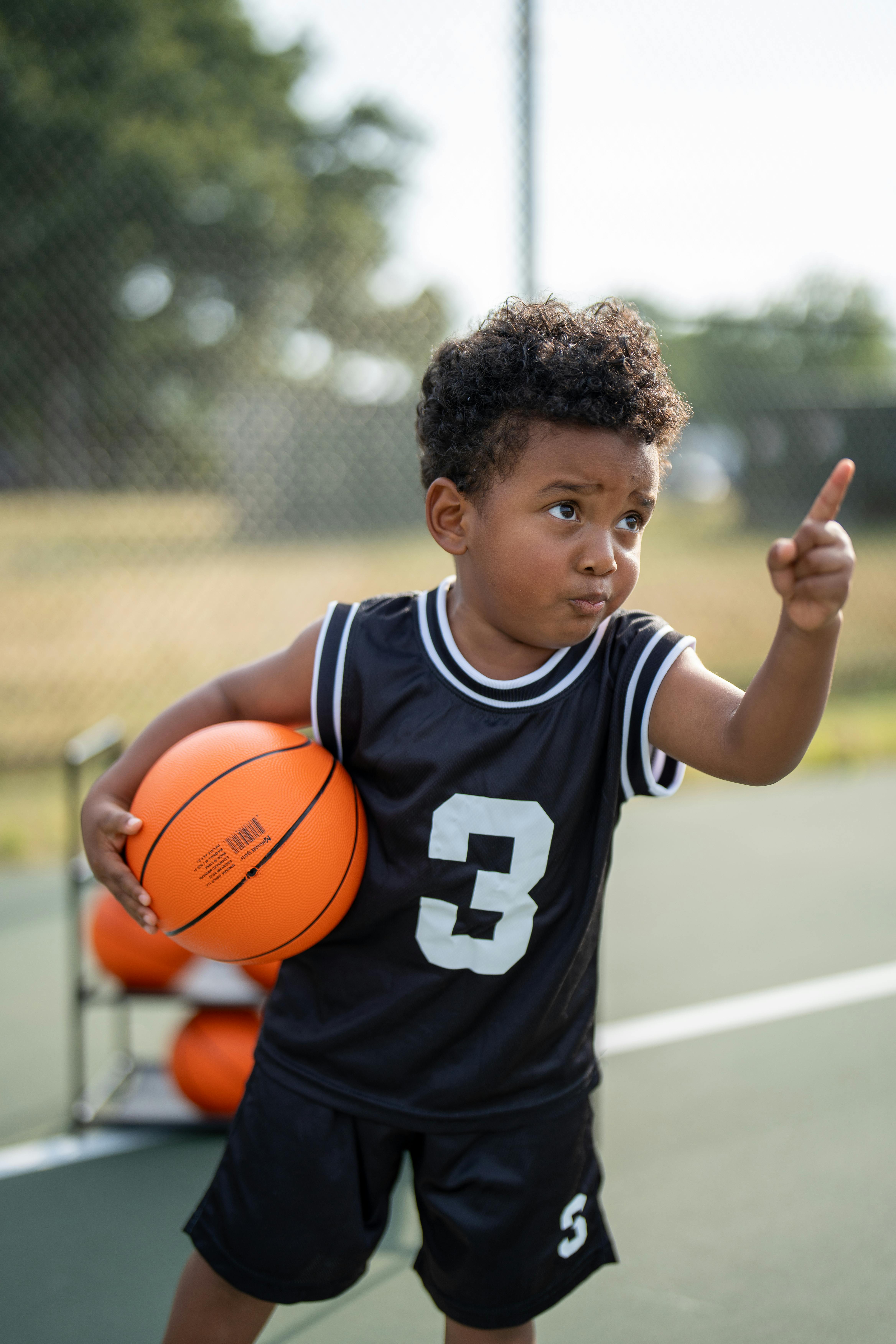 Young Child Playing Basketball on Outdoor Court · Free Stock Photo