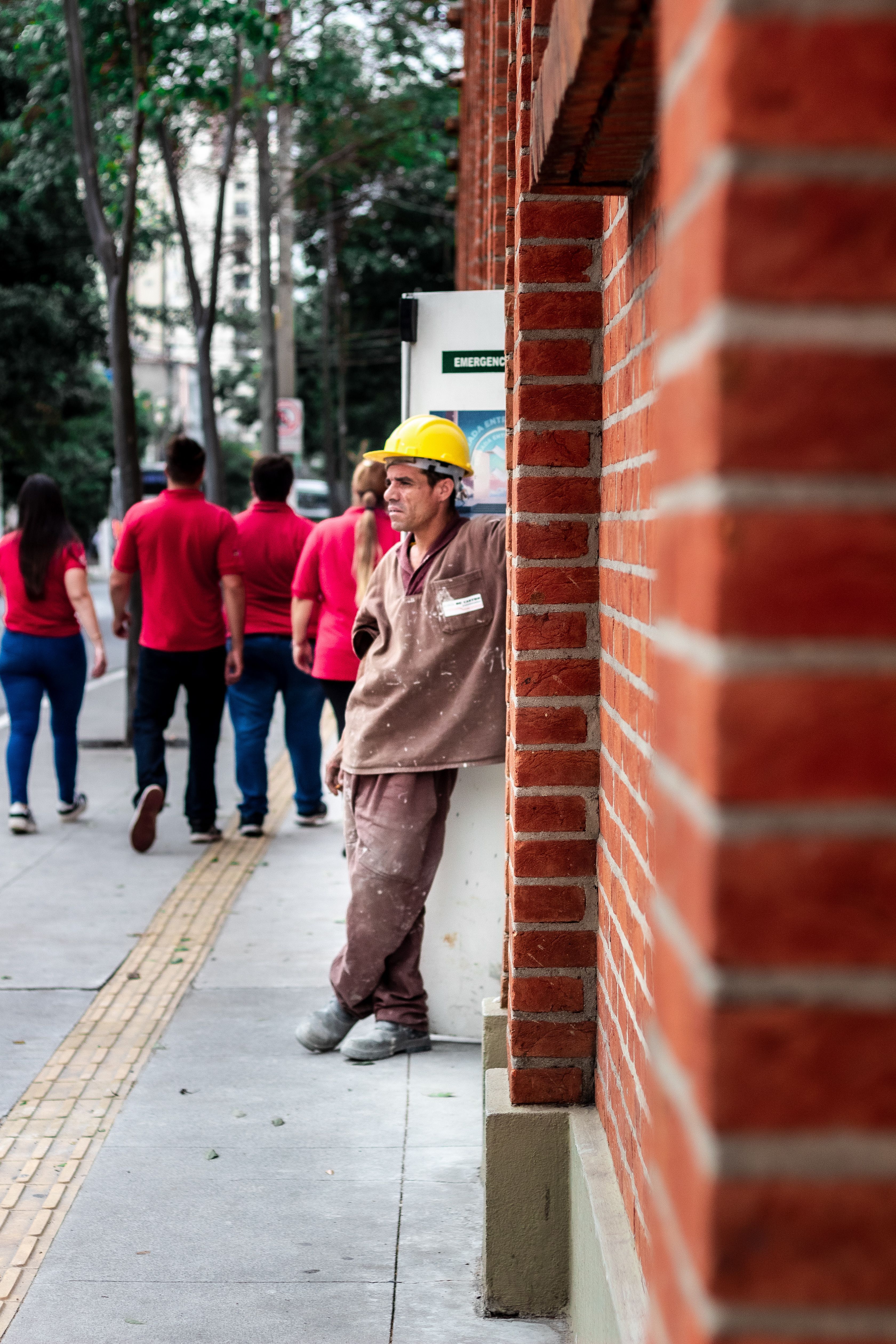 Construction Worker Leaning Against Brick Wall · Free Stock Photo