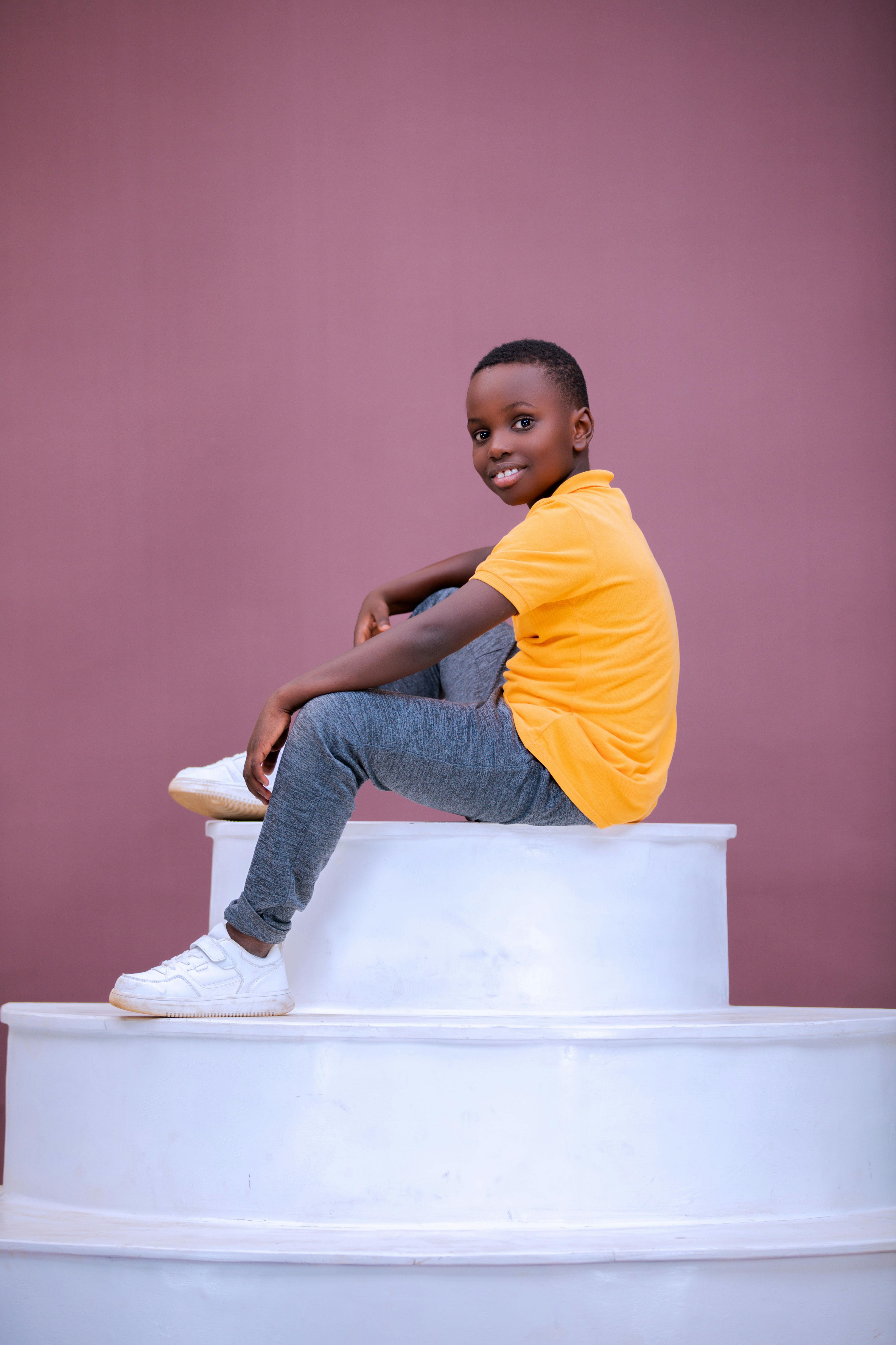 Smiling Child Posing on White Steps Indoors · Free Stock Photo