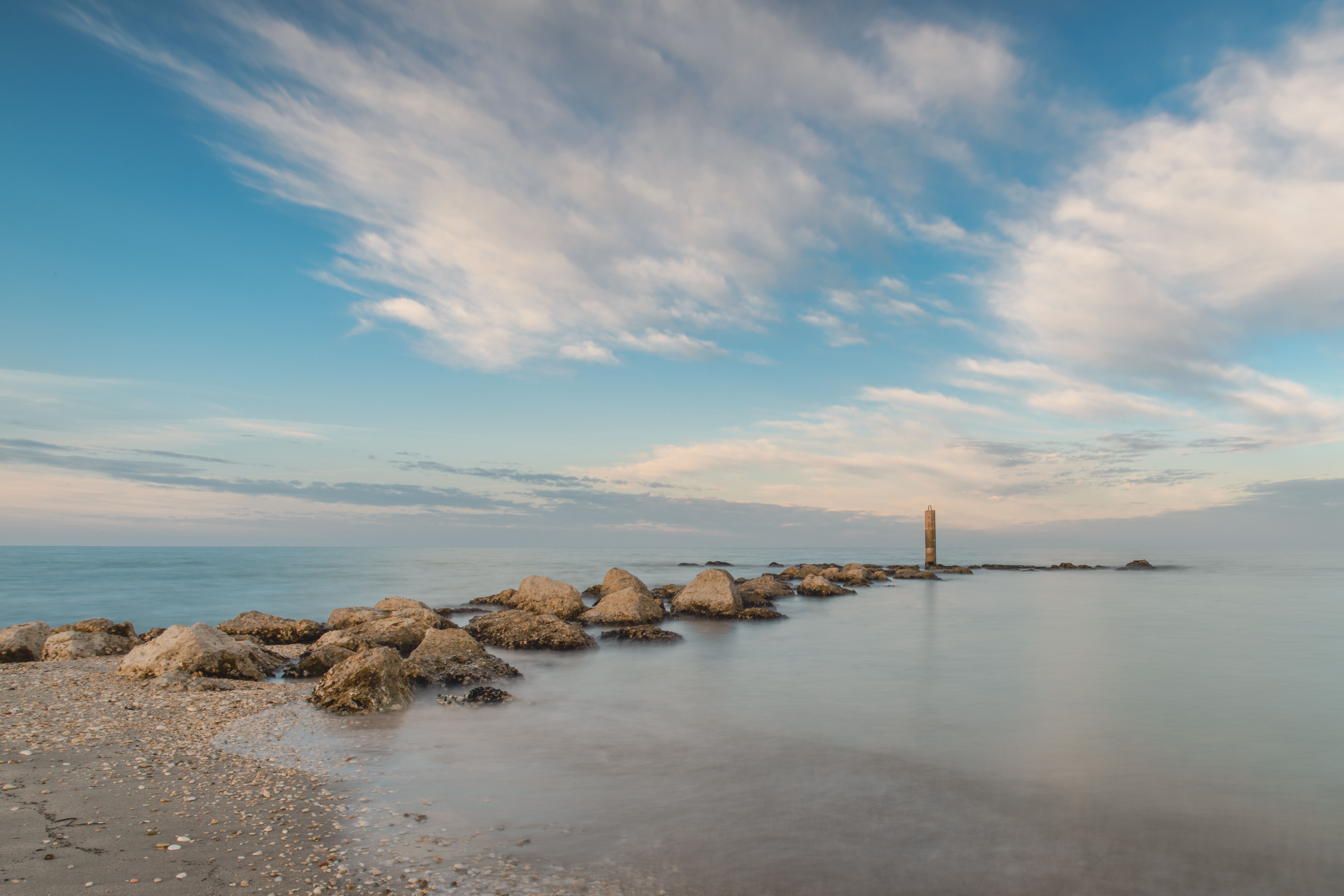 Serene Coastal Landscape with Breakwater and Tower · Free Stock Photo