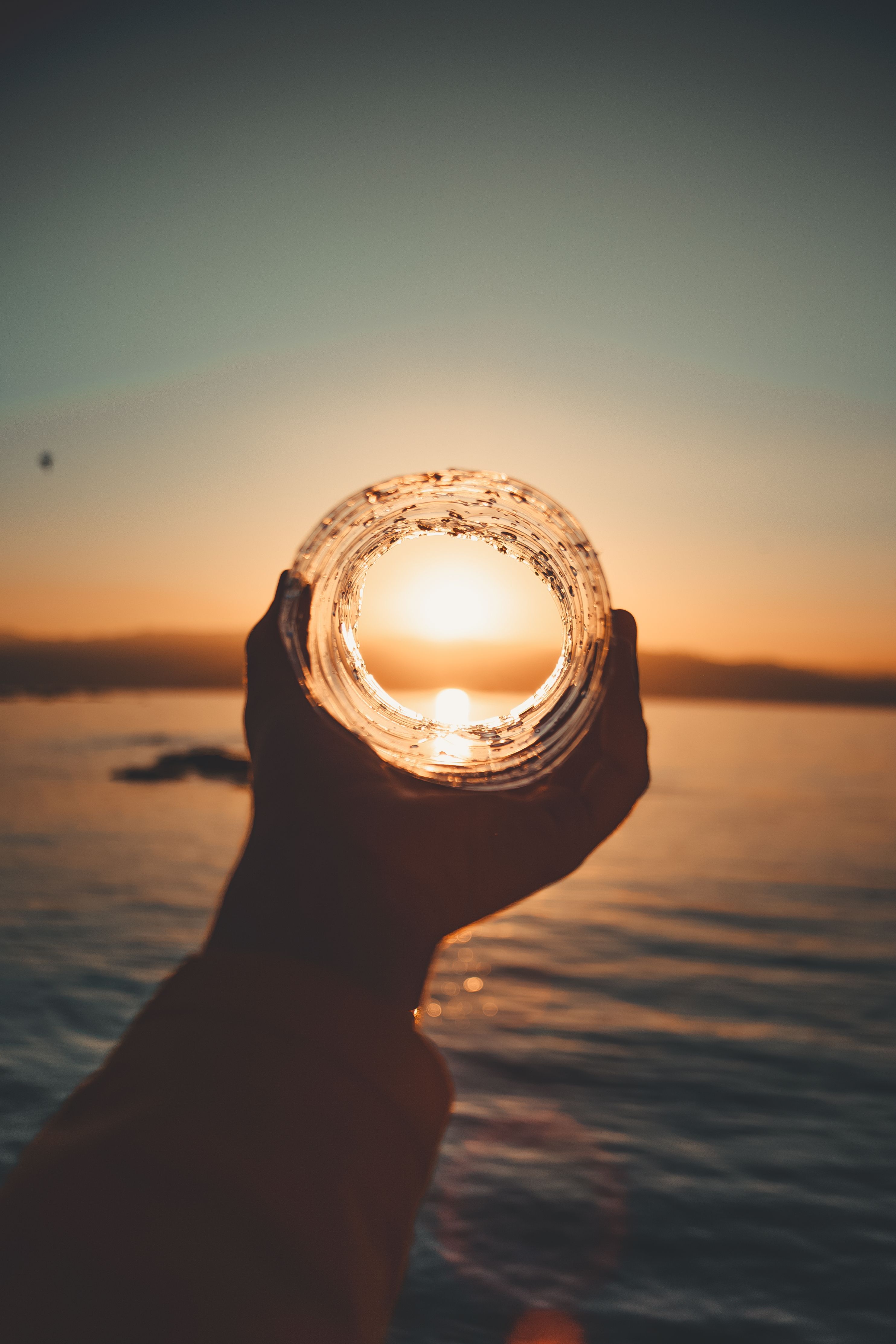 Crop anonymous tourist showing bright sunset through glass near sea ...