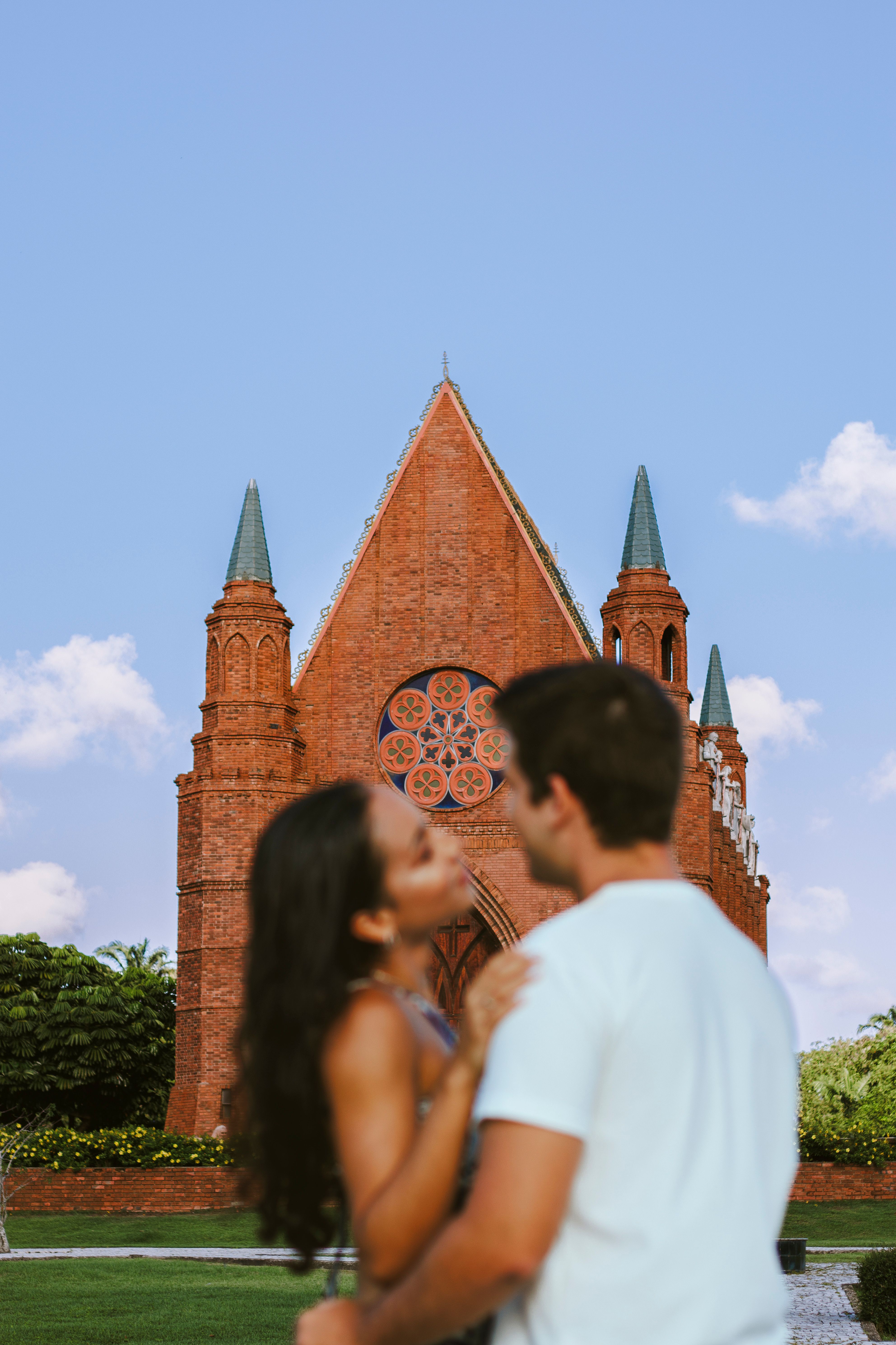 Romantic Couple Embracing in Front of Brick Church · Free Stock Photo