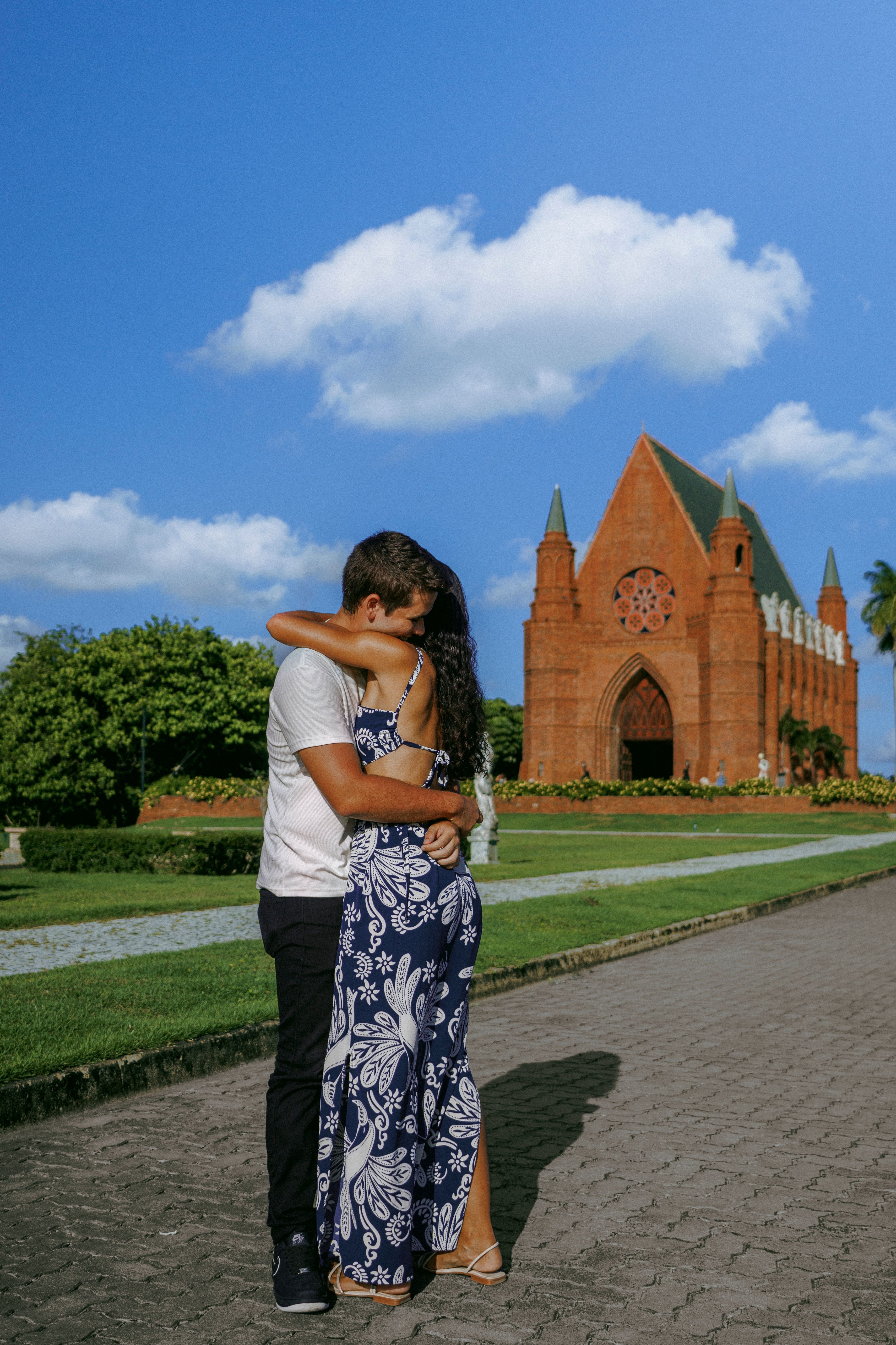 Romantic Embrace Near Historic Brick Church · Free Stock Photo