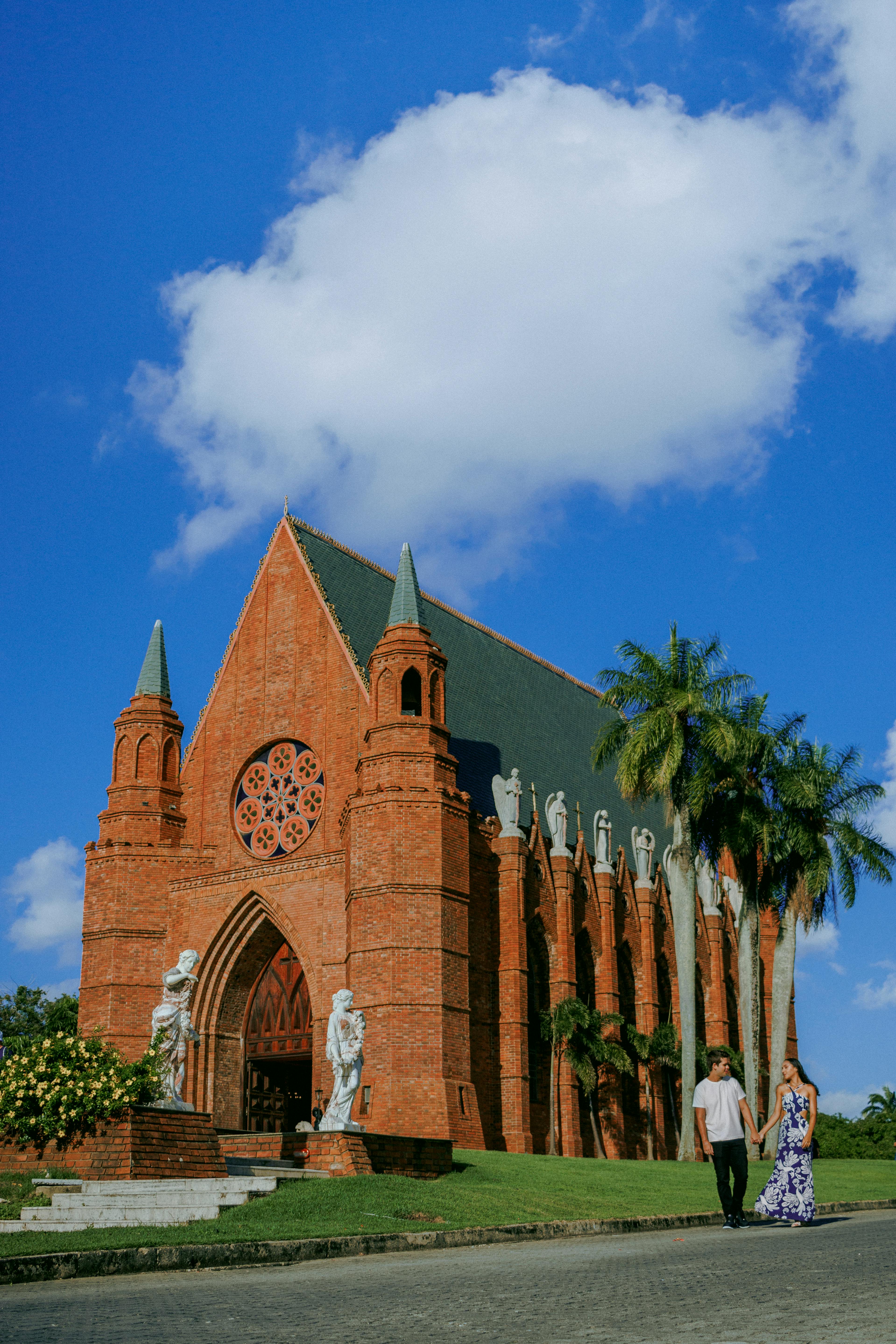 Red Brick Gothic Chapel with Palm Trees in Sunlight · Free Stock Photo
