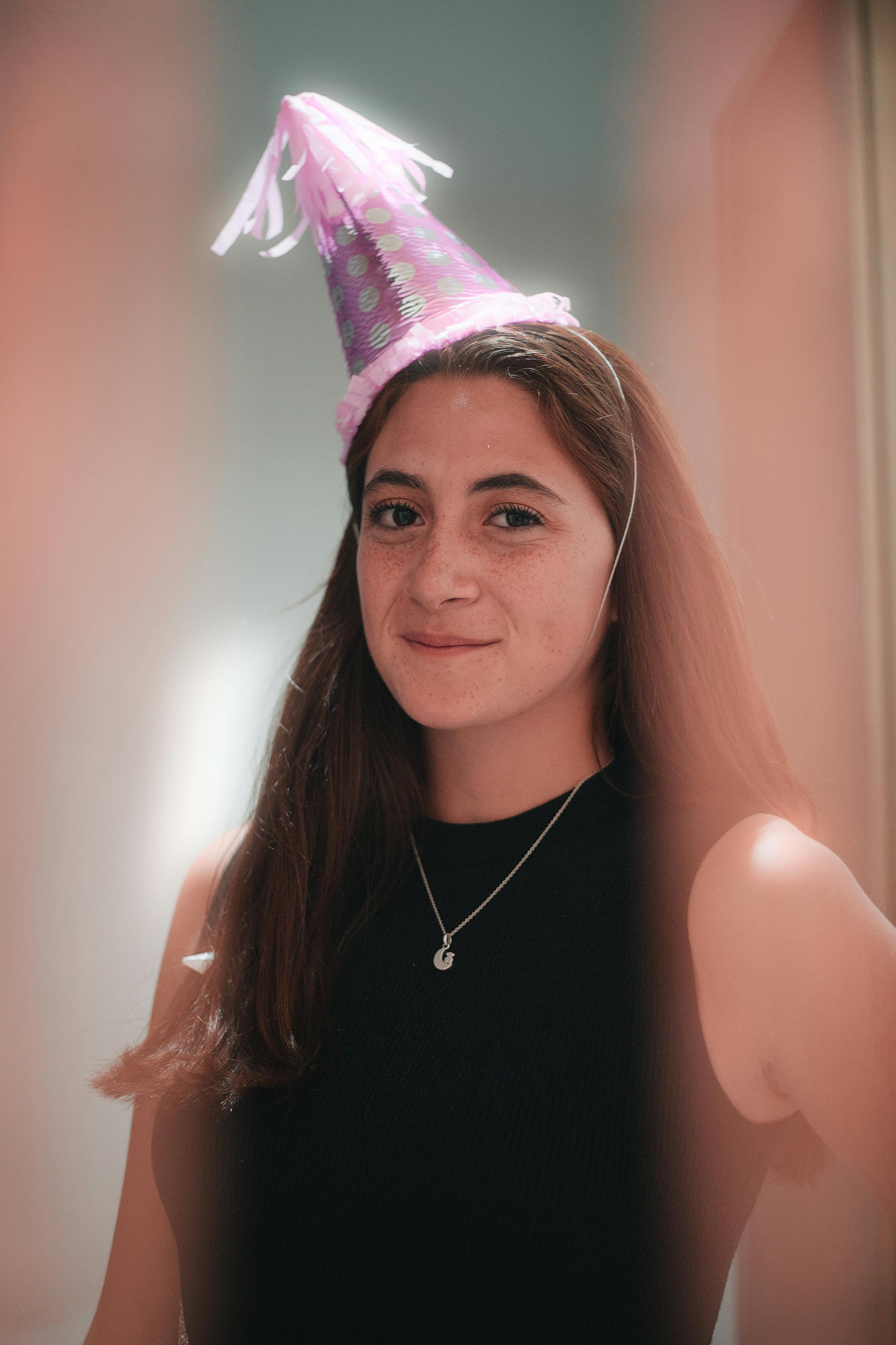 Woman Celebrating with Pink Party Hat Indoors · Free Stock Photo