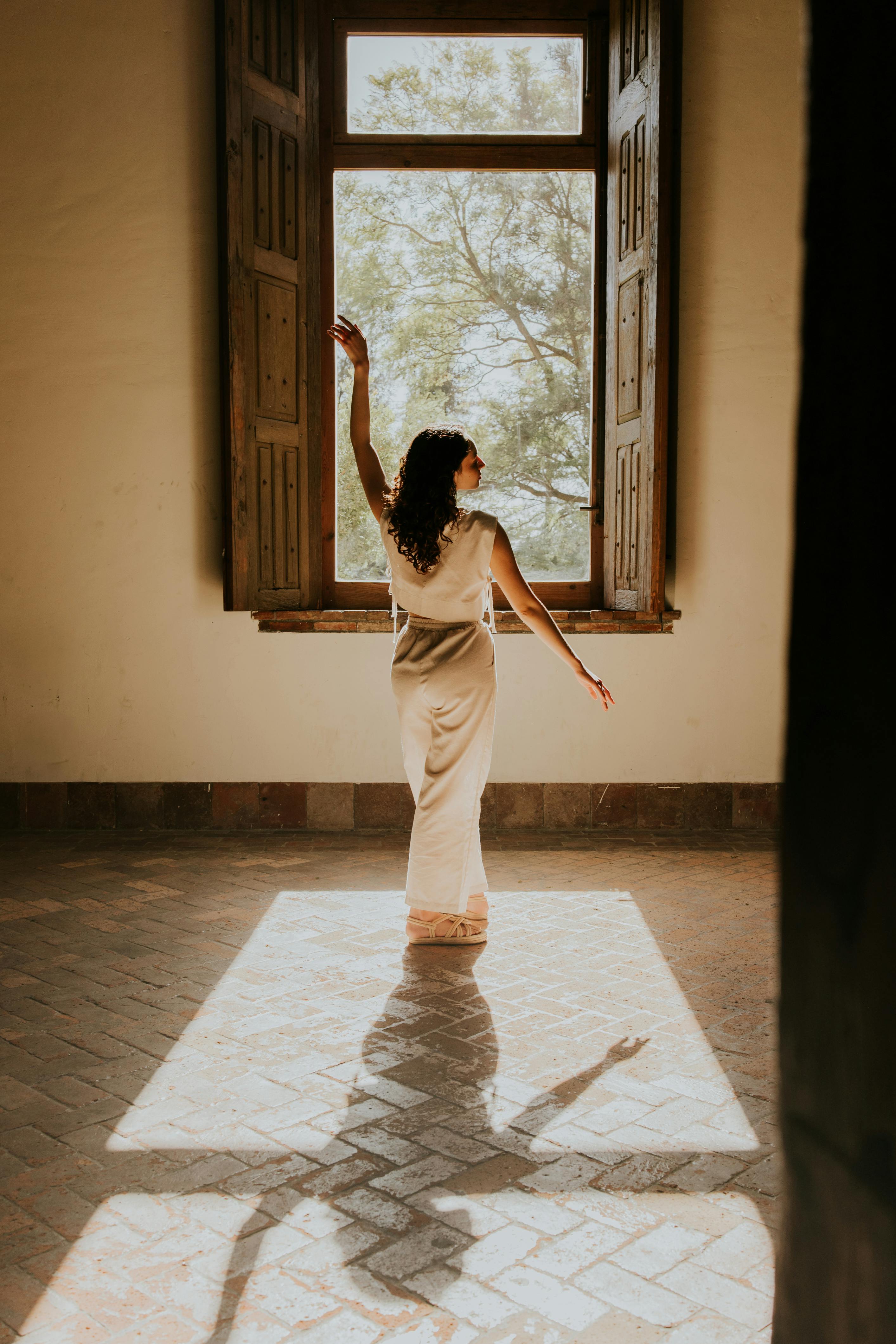 Graceful Woman Dancing in Sunlit Window Room · Free Stock Photo