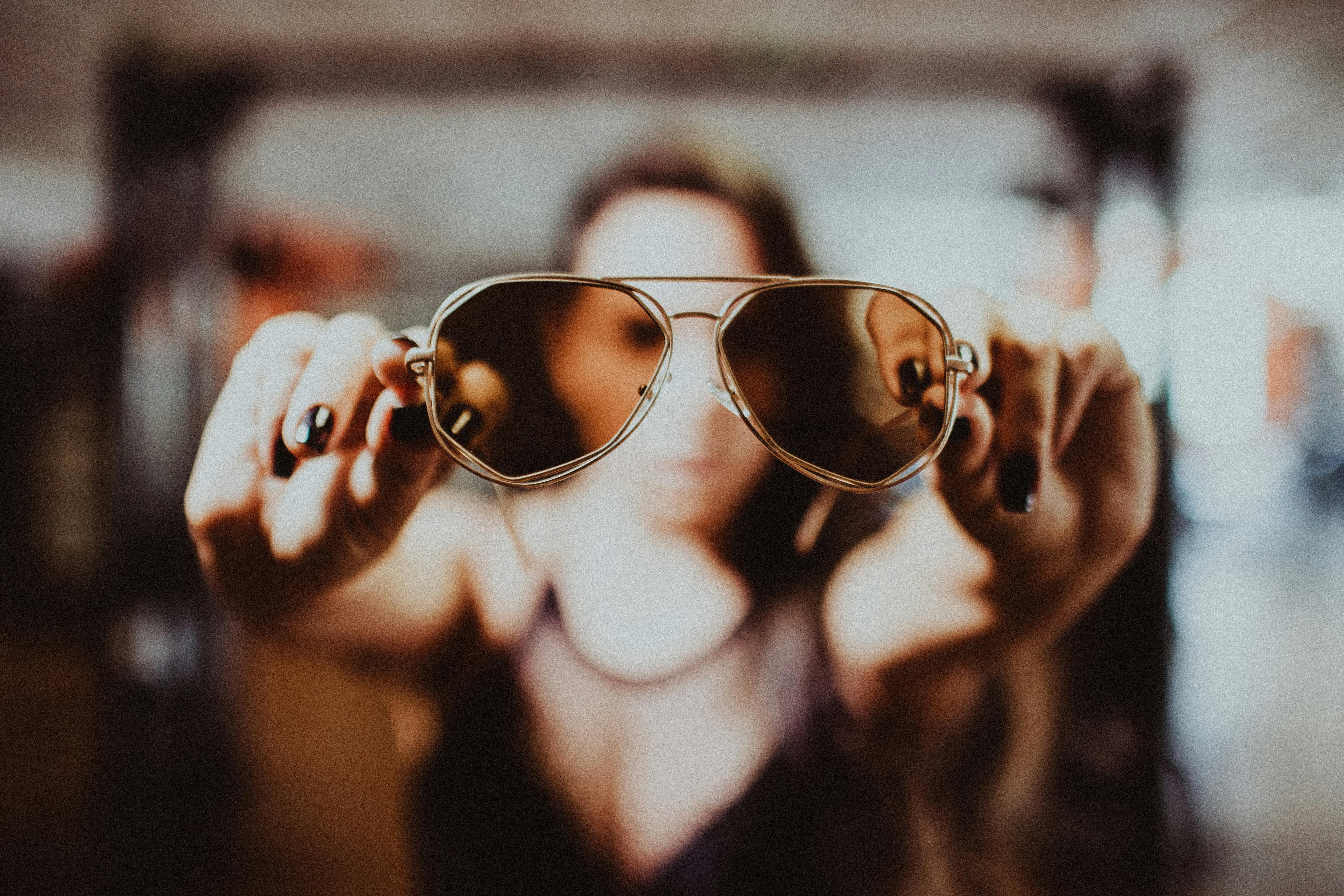 Shallow Focus Photo of Person's Hand Holding Sunglasses · Free Stock Photo