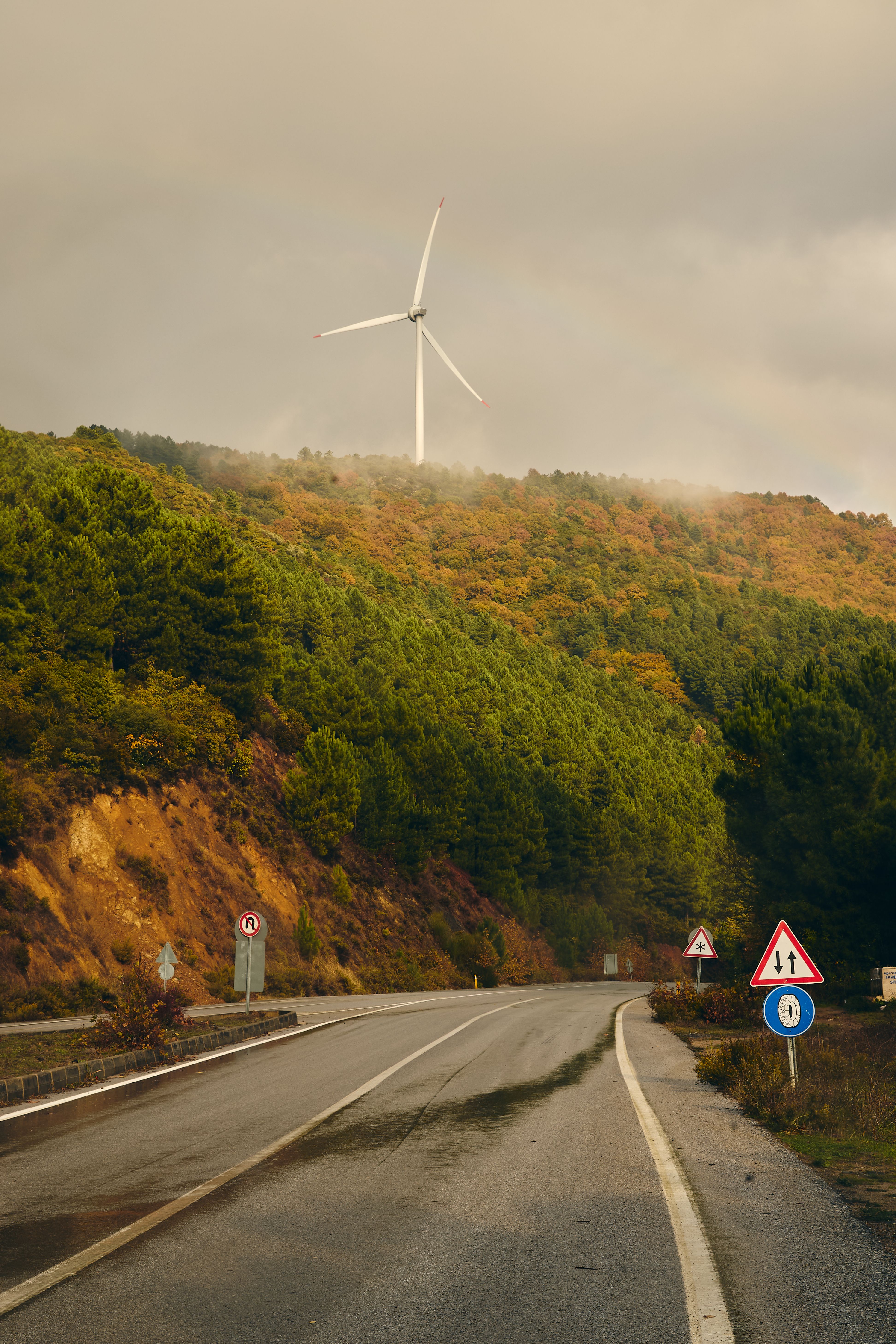 Wind Turbine on Rainy Mountain Road Landscape · Free Stock Photo