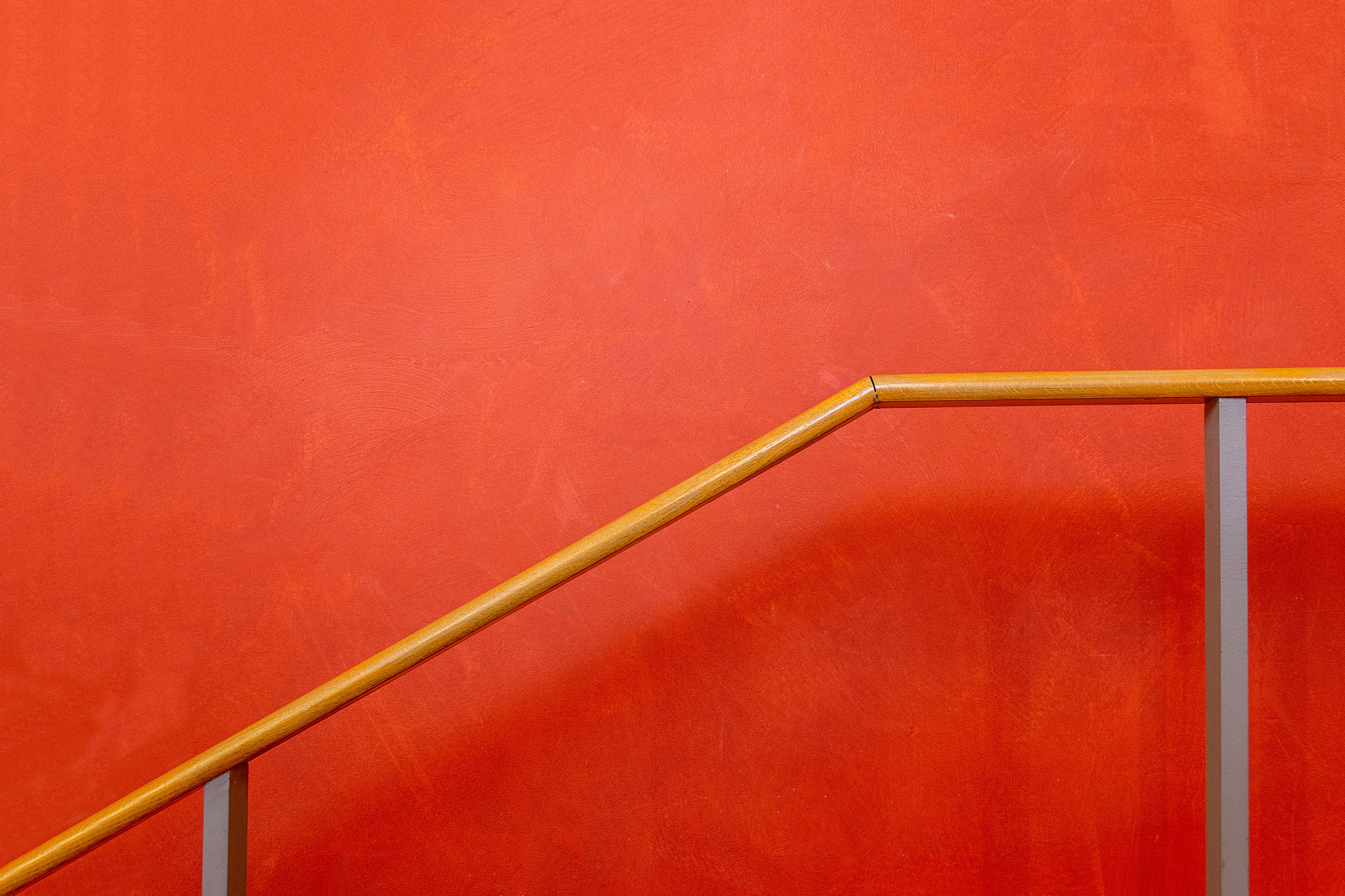 Minimalist Wooden Railing Against Bold Red Wall · Free Stock Photo