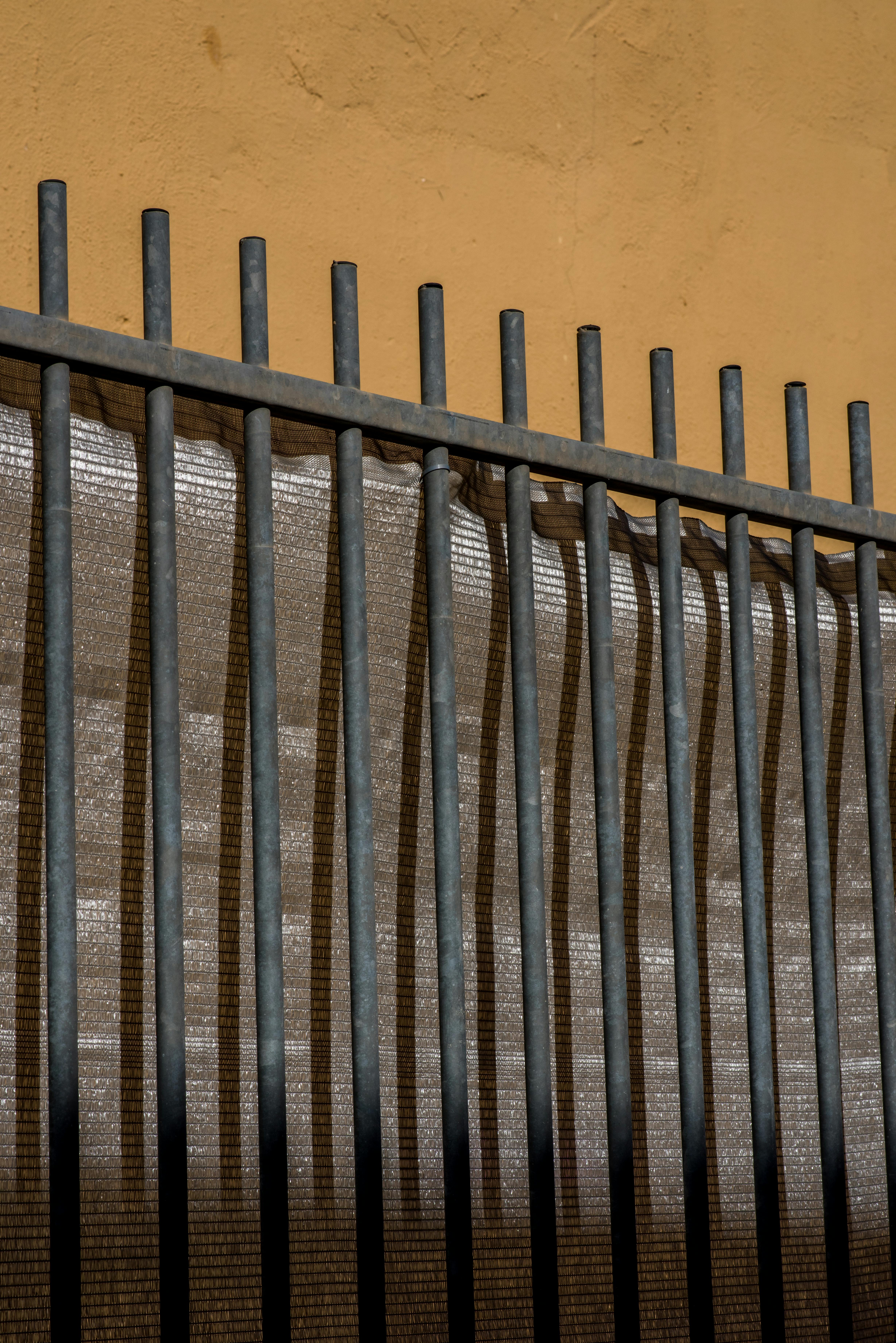 Metal Fence Casting Shadows on Yellow Wall · Free Stock Photo