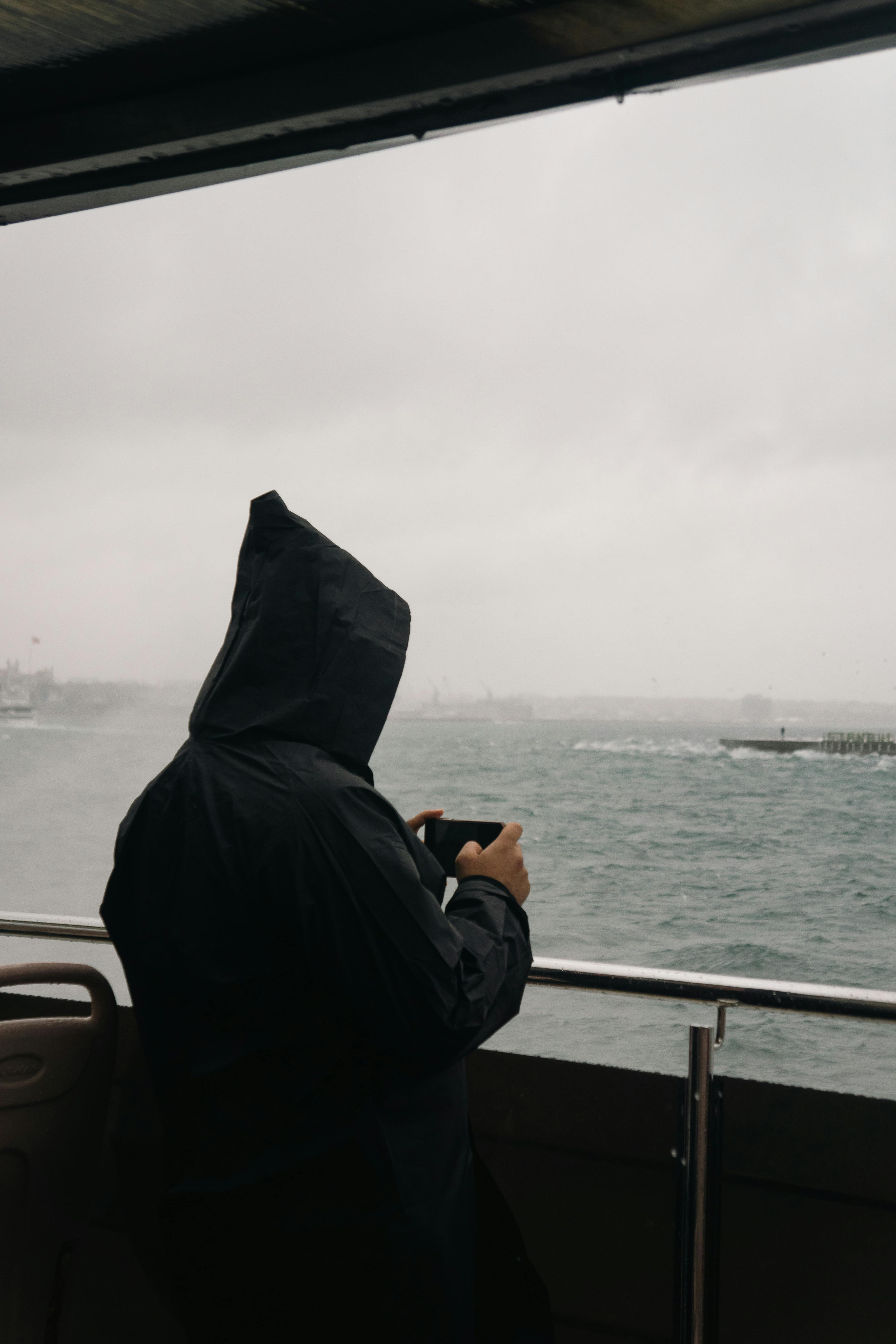 Person in Raincoat Photographing Stormy Seas · Free Stock Photo