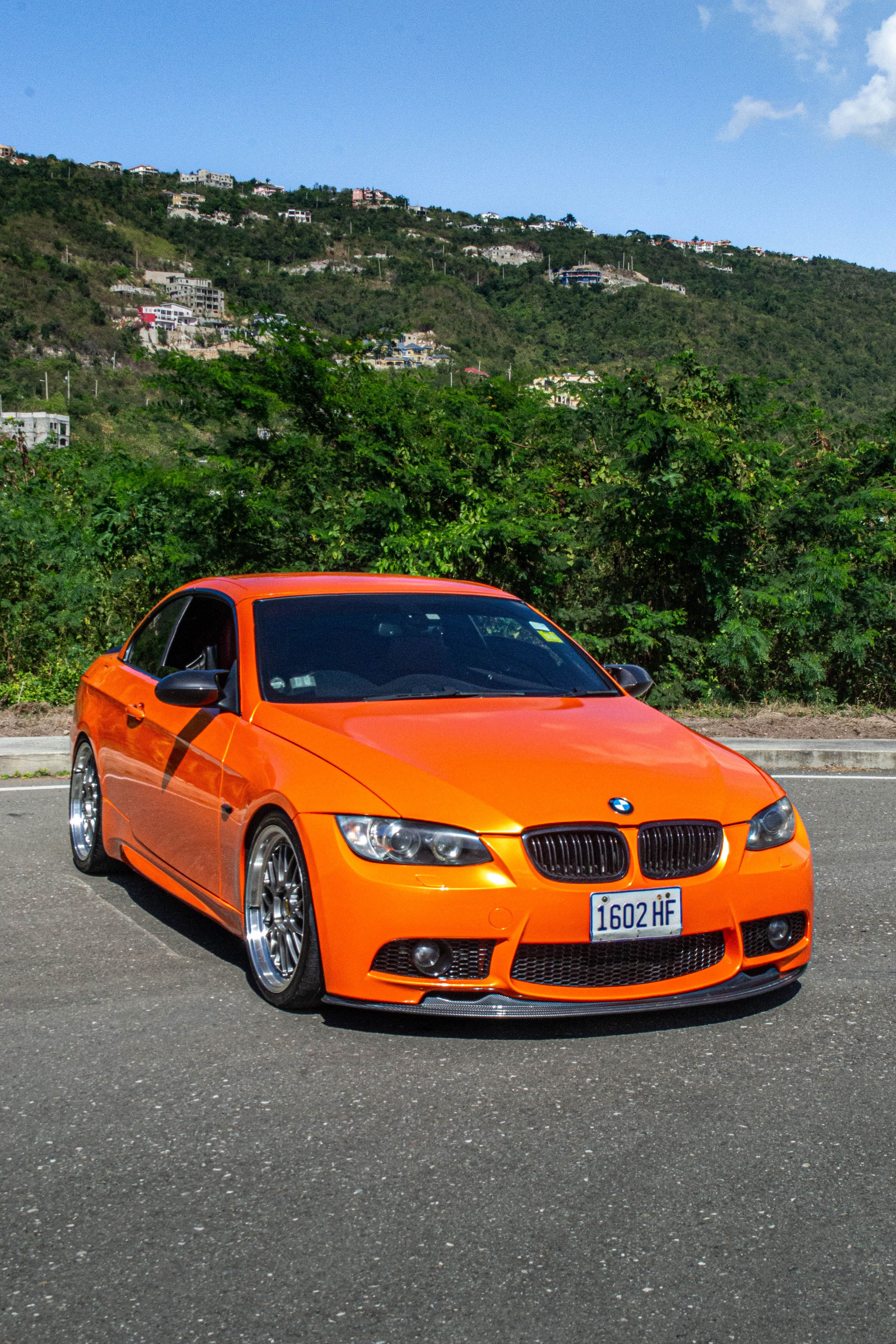 Vibrant Orange BMW Car on Scenic Road · Free Stock Photo