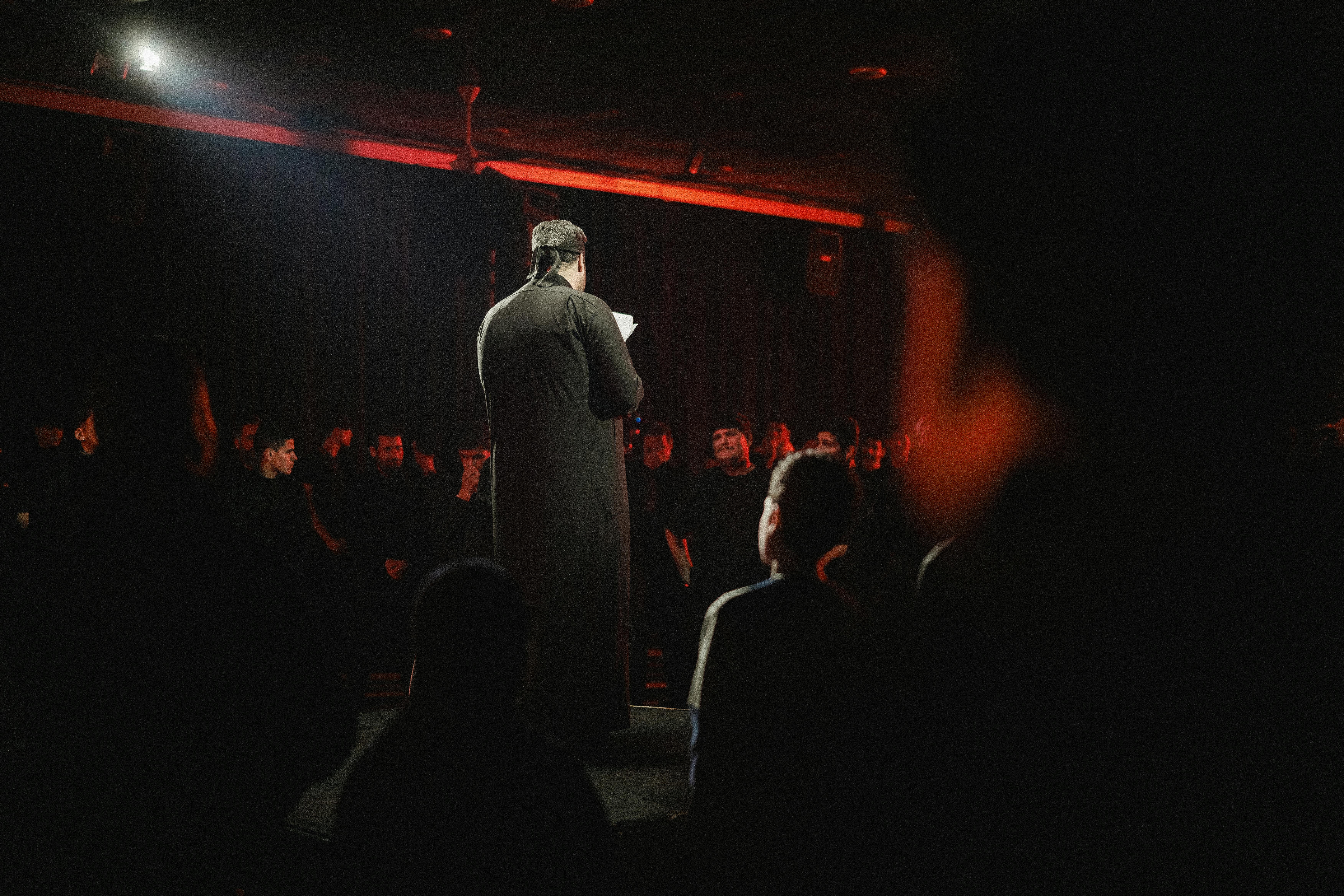Silhouette of Speaker Addressing Crowd in Dimly Lit Room · Free Stock Photo