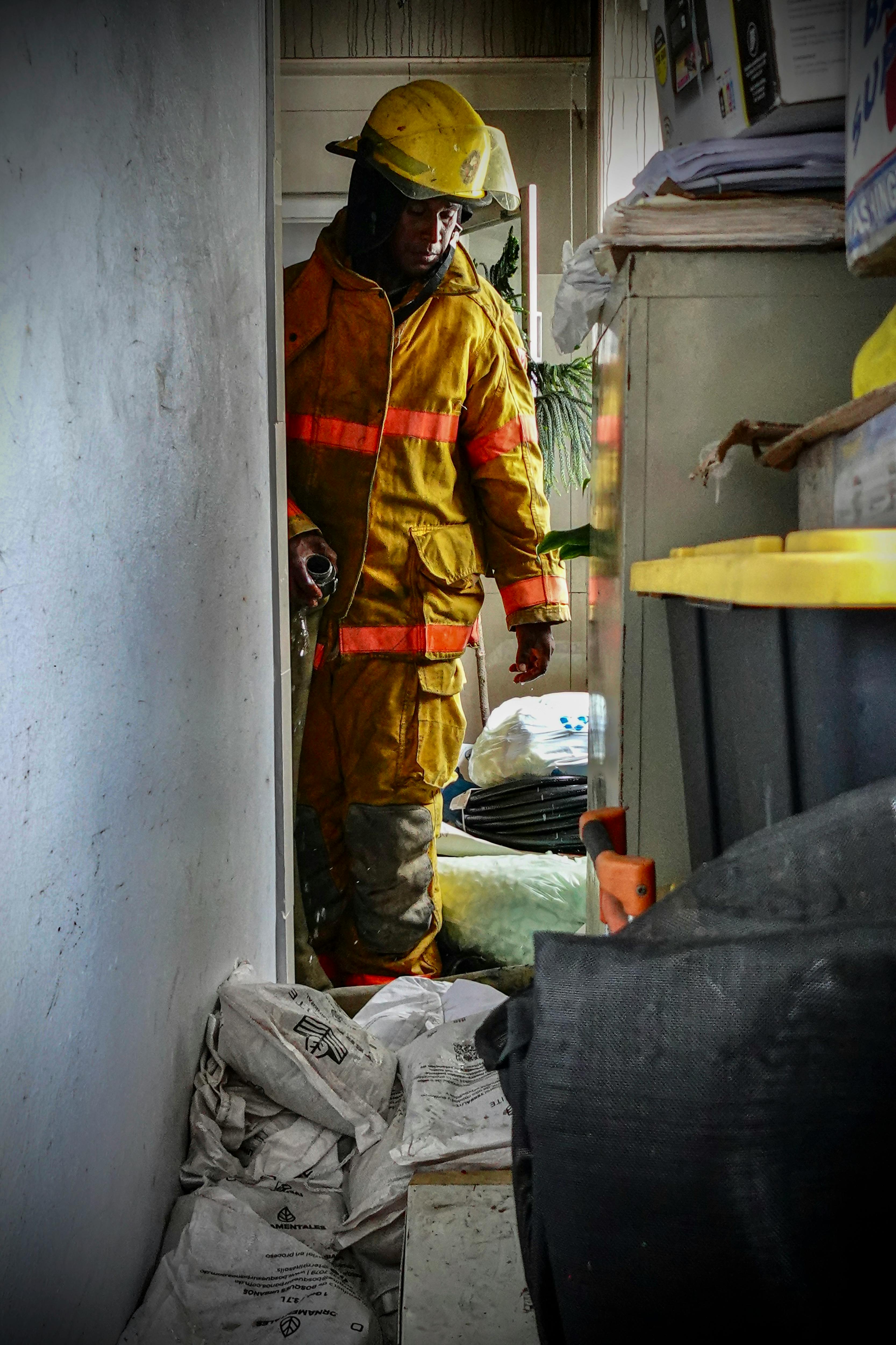 Firefighter in Protective Gear Inside a Cluttered Room · Free Stock Photo