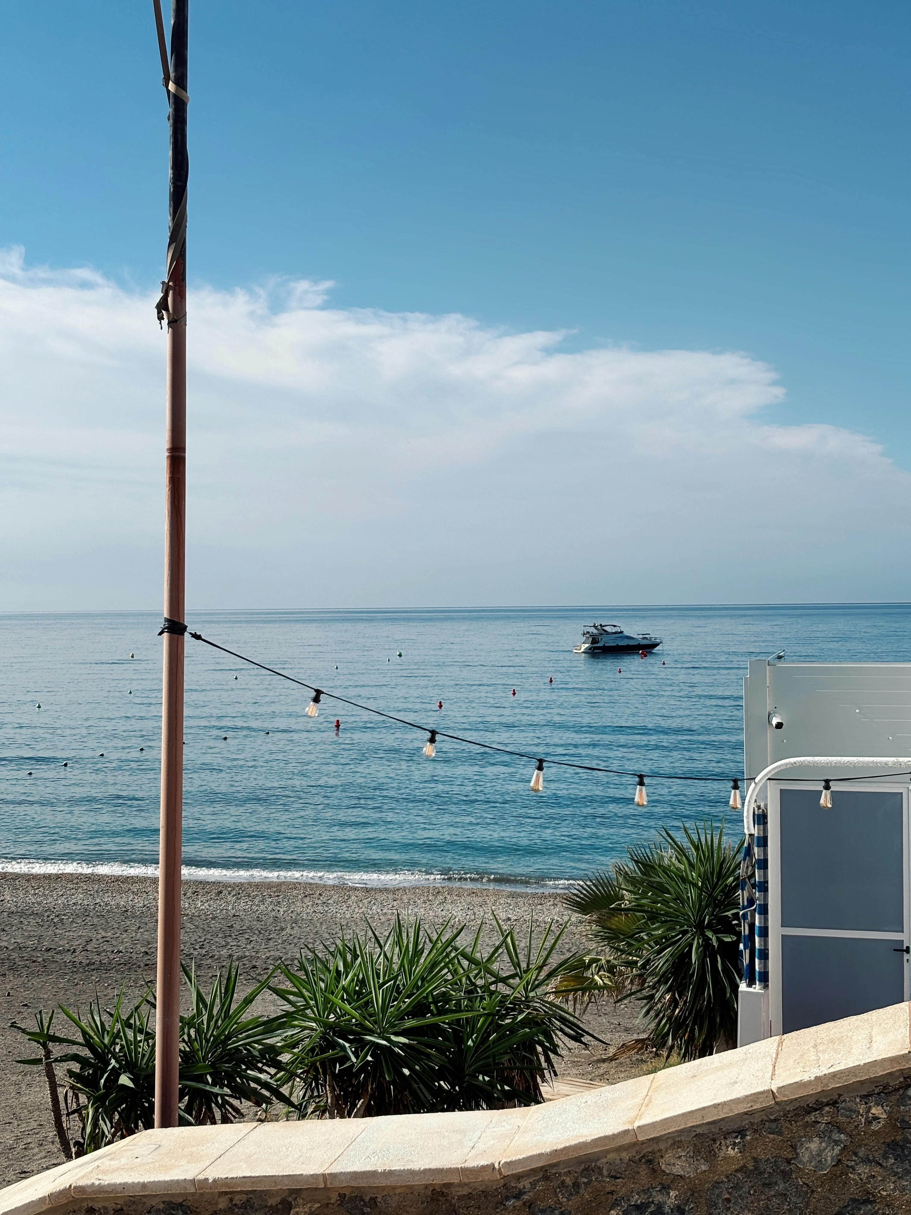 Tranquil Beachfront Scene with Boat in Distance · Free Stock Photo