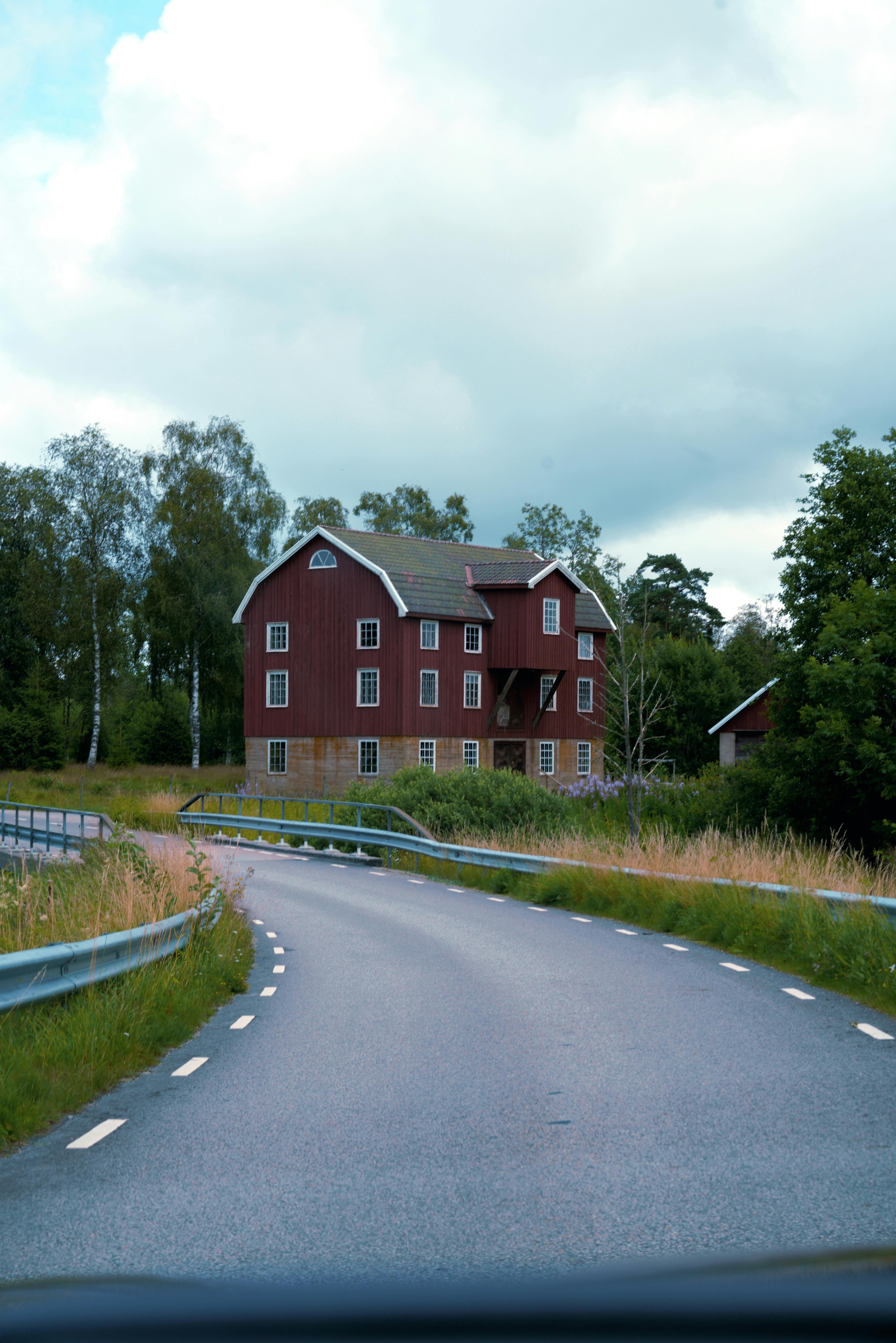 Scenic Rural Road with Red Wooden Farmhouse · Free Stock Photo