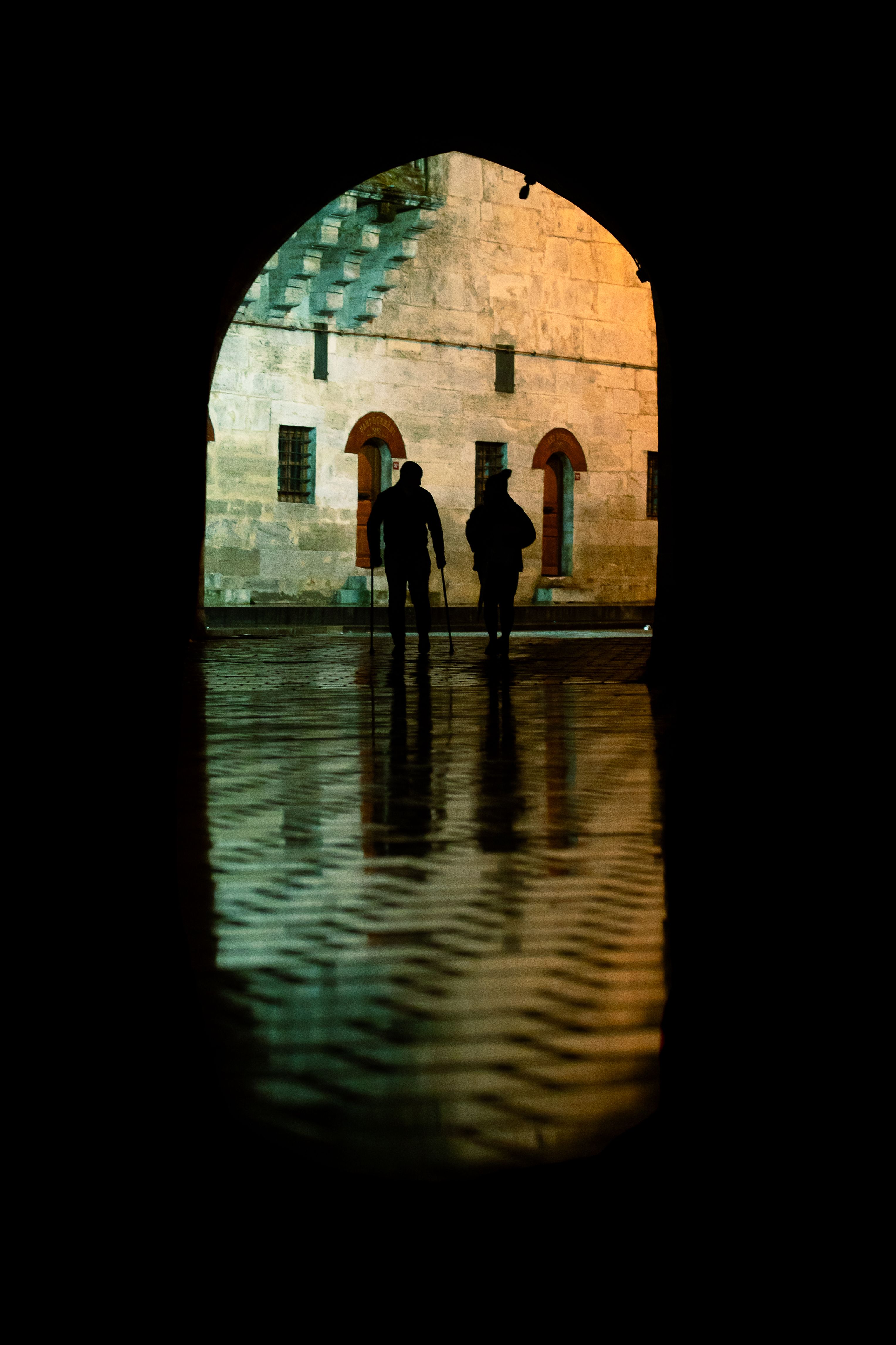 Silhouetted figures in illuminated archway night scene · Free Stock Photo