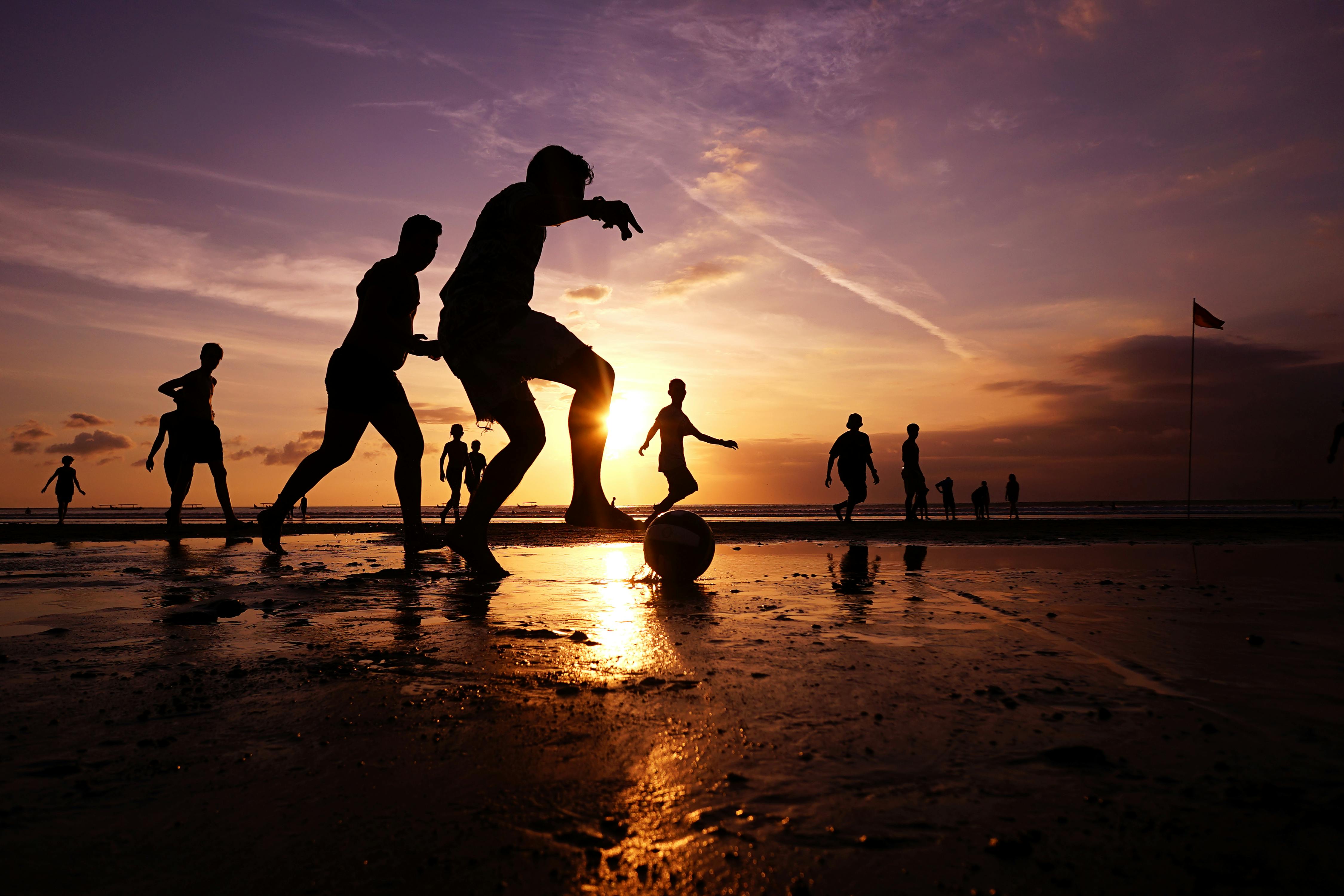 Vibrant Beach Football Game at Bali Sunset · Free Stock Photo