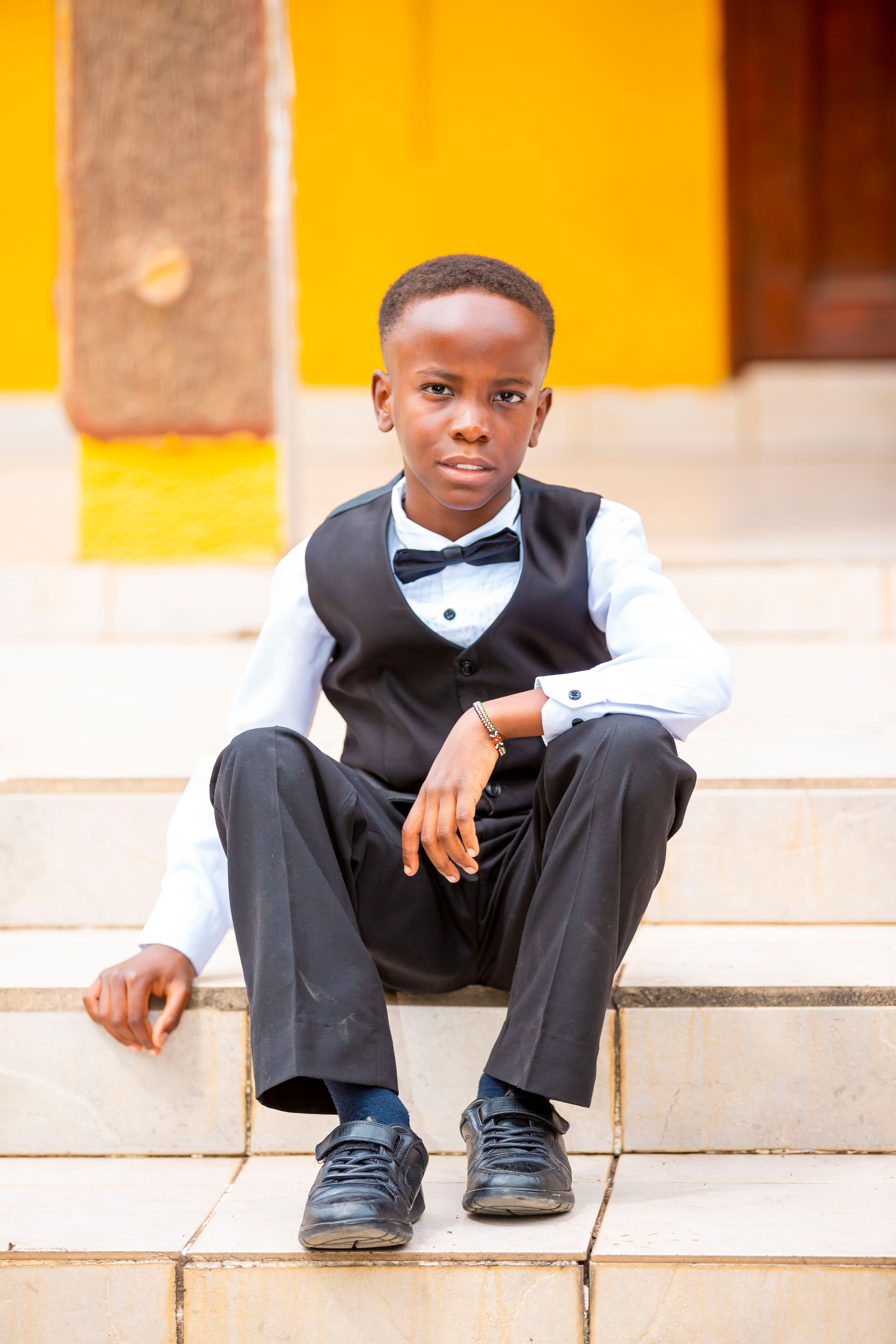 Elegant Young Boy in Formal Attire on Steps · Free Stock Photo