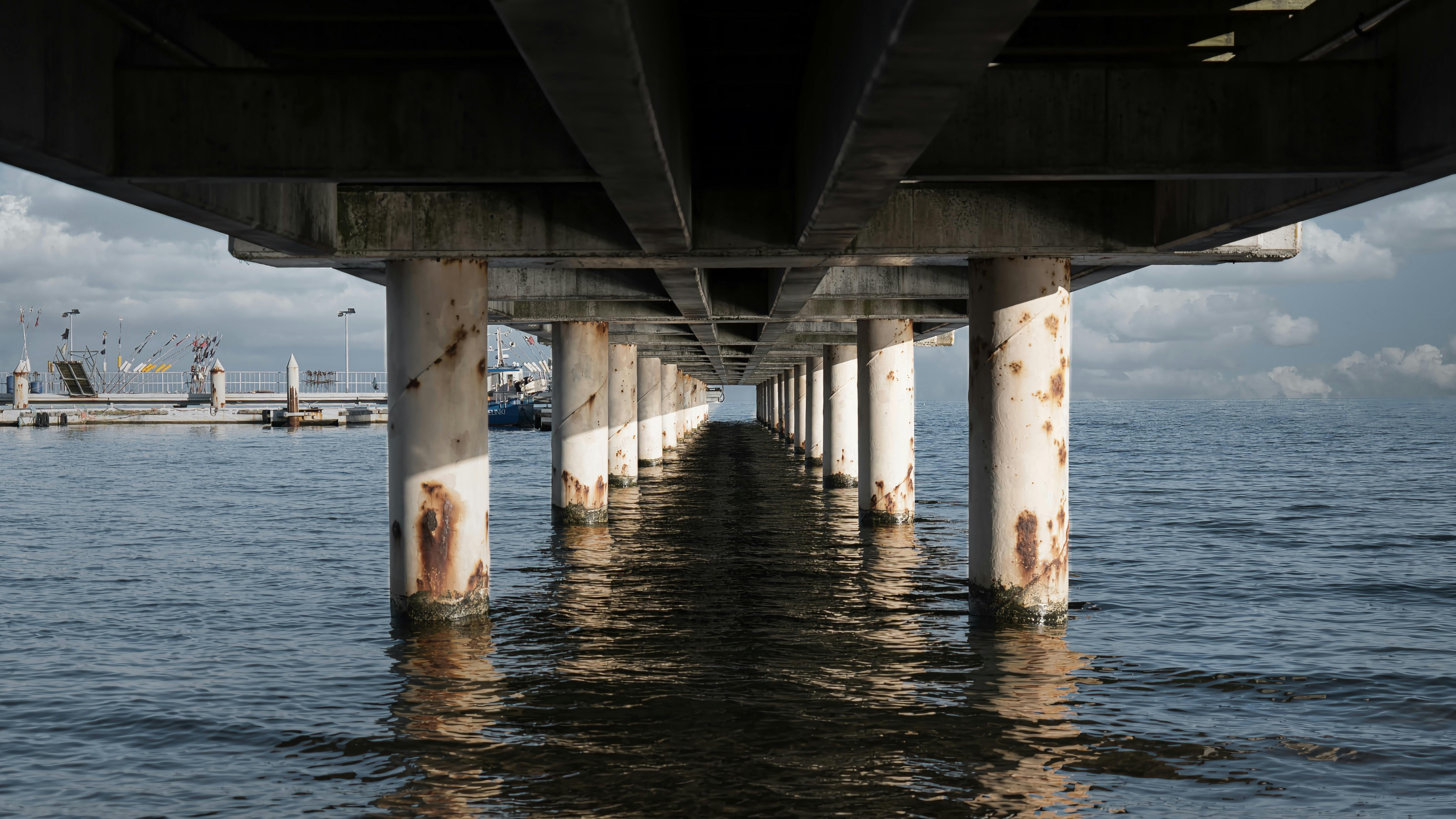Underneath a Rusty Bridge over Ocean Waters · Free Stock Photo