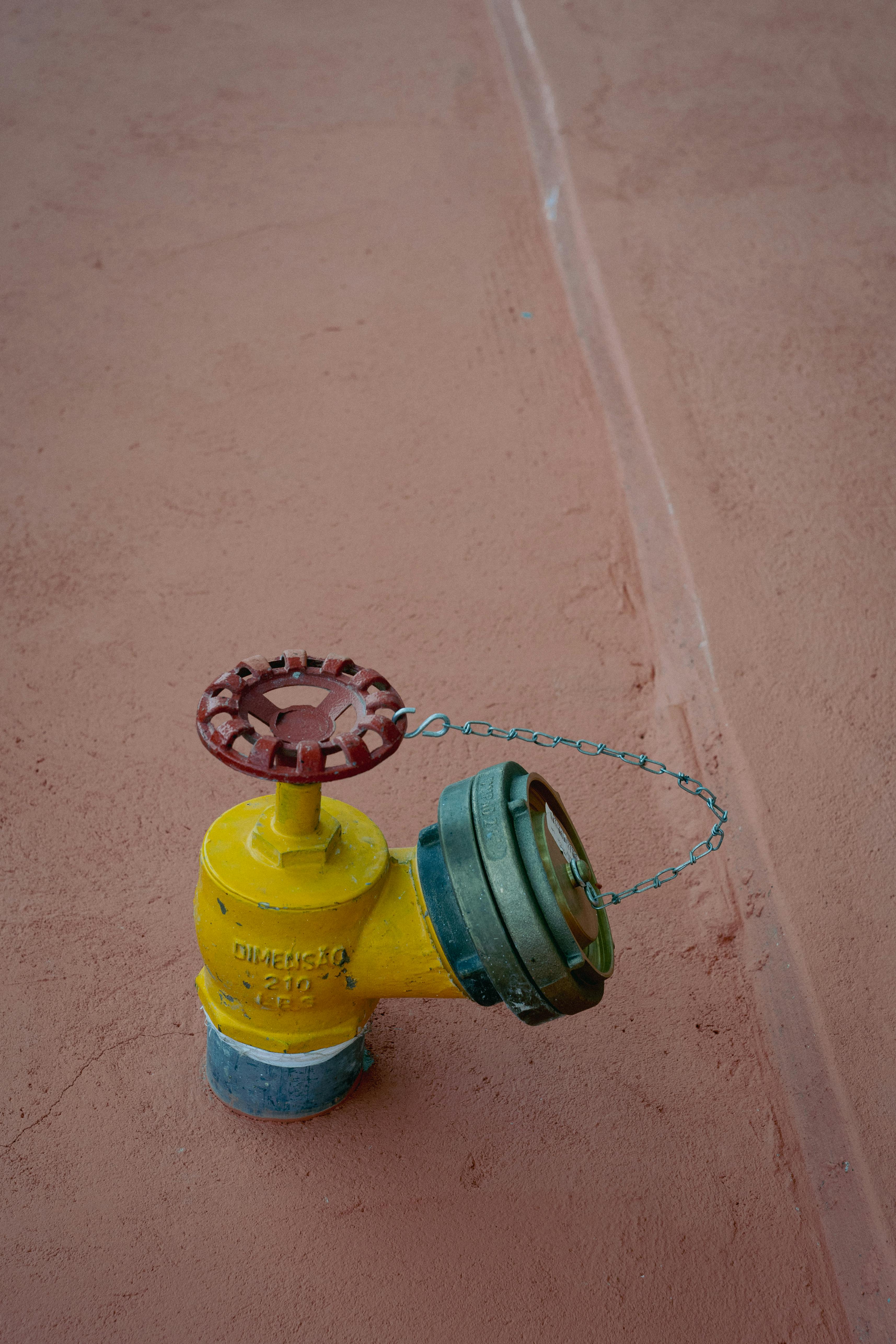 Bright Yellow Hydrant on Red Concrete Surface · Free Stock Photo