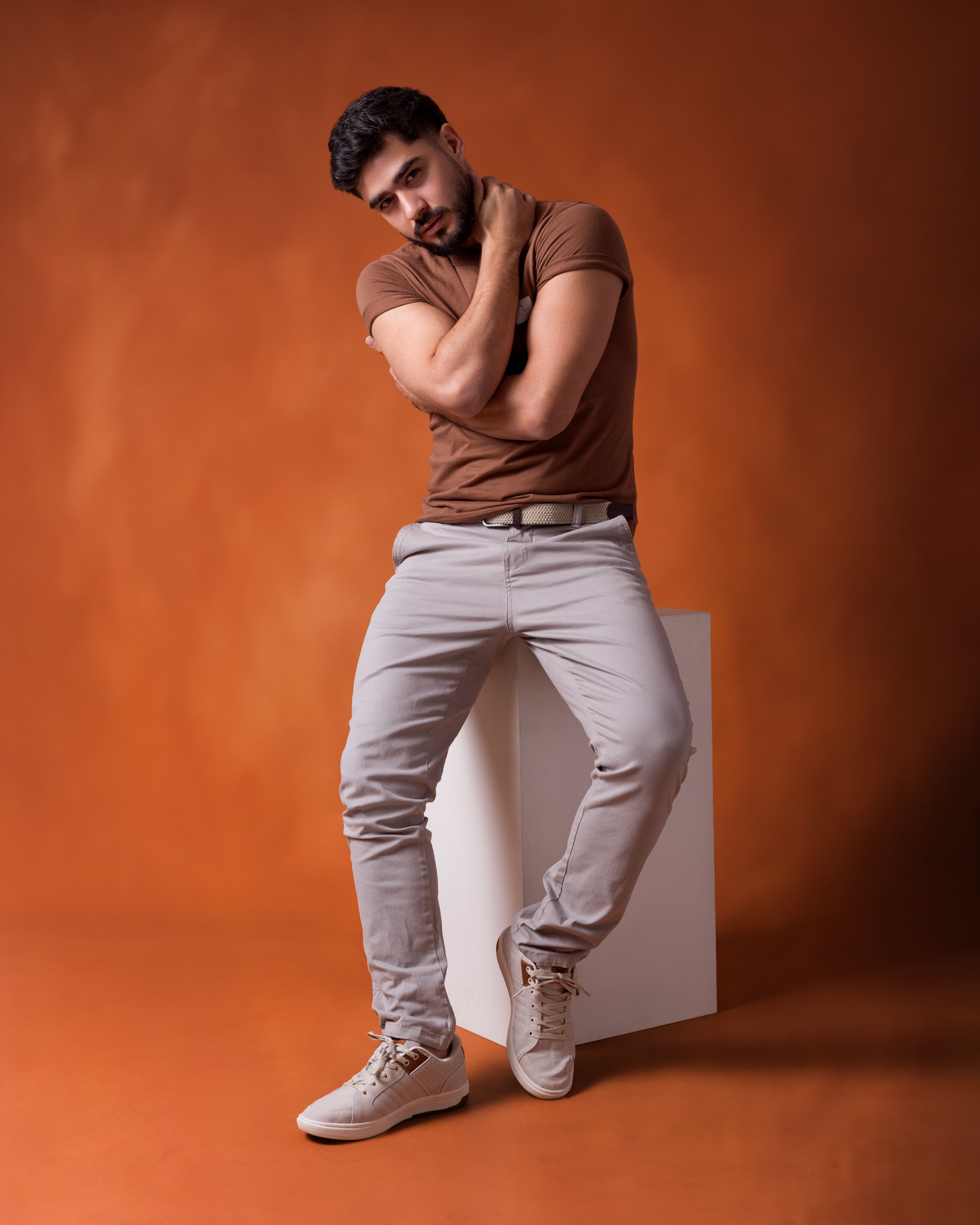Stylish Man Posing in Studio Against Orange Background · Free Stock Photo