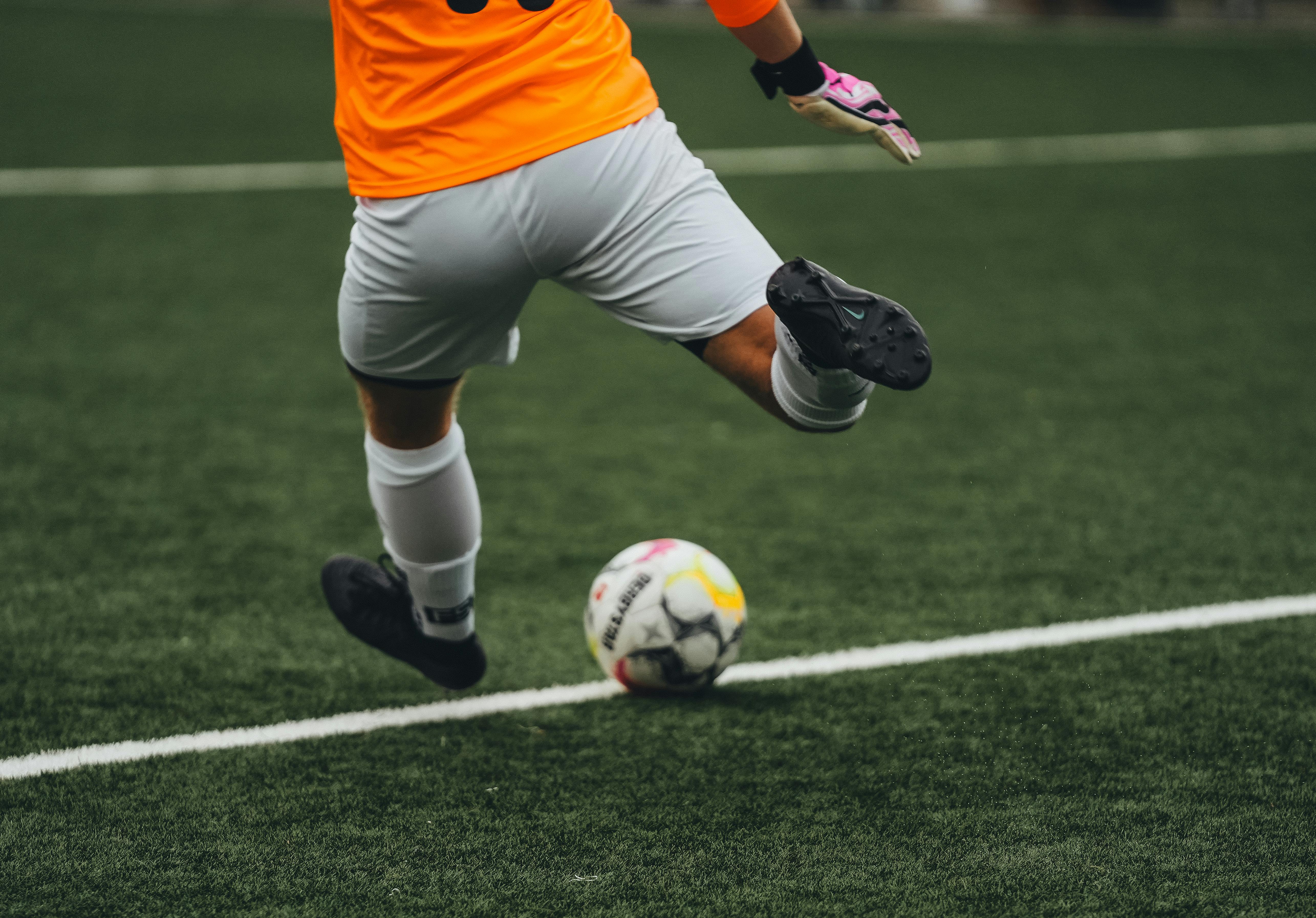 Soccer Player Kicking Ball on Field · Free Stock Photo