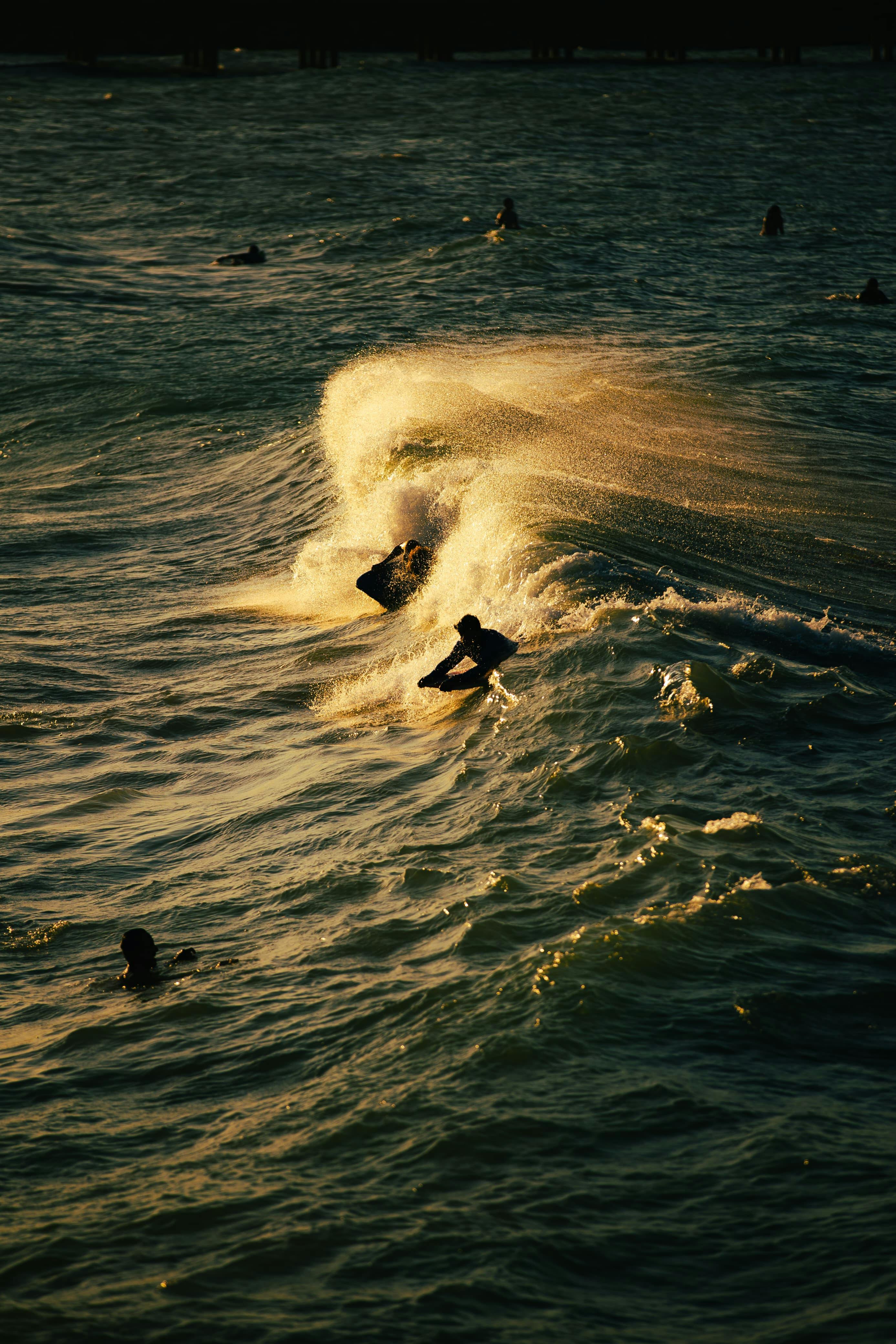 Sunset Surfing Scene with Surfers Riding Waves · Free Stock Photo