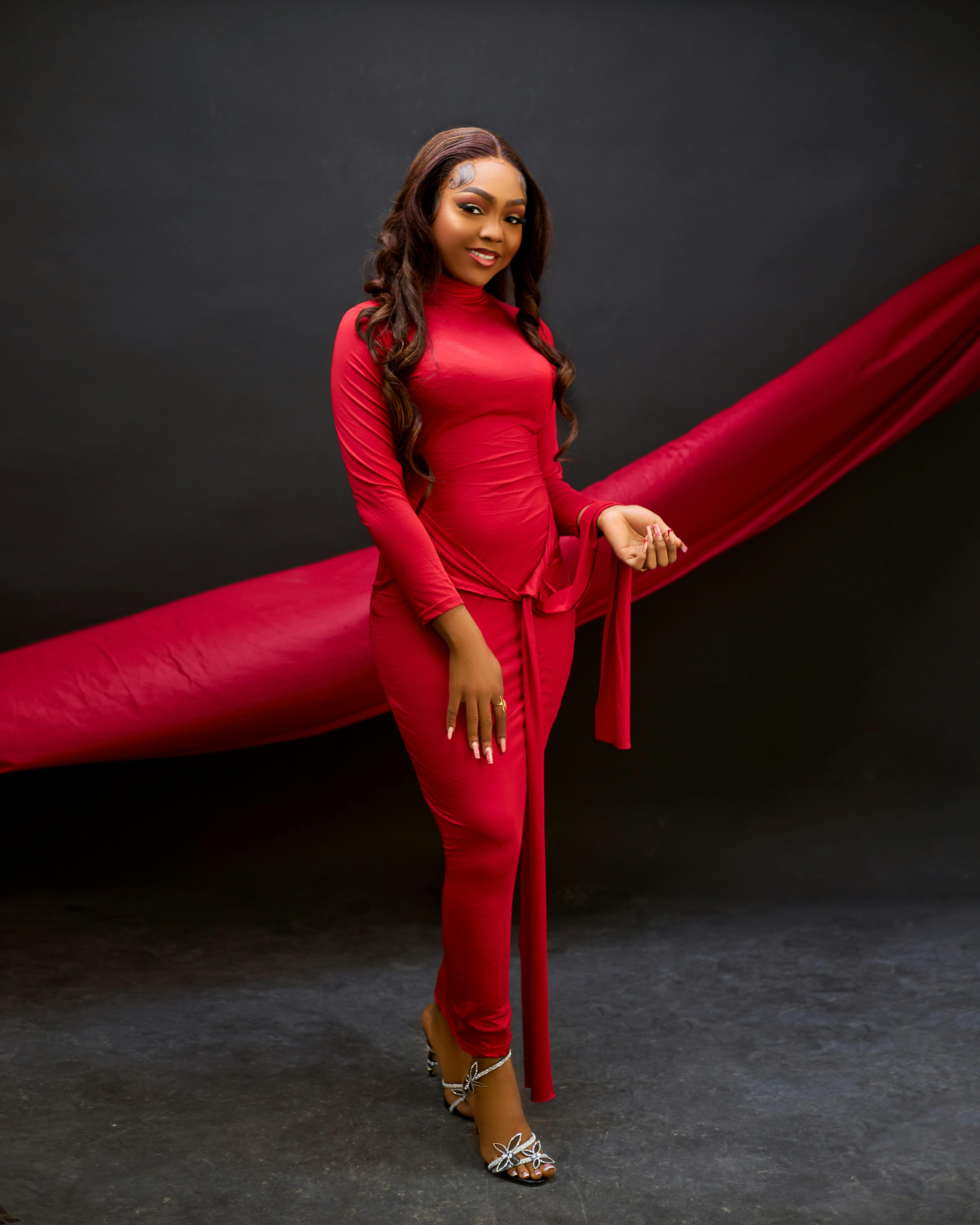 Elegante Vrouw In Rode Jurk Tegen Donkere Achtergrond · Gratis stockfoto