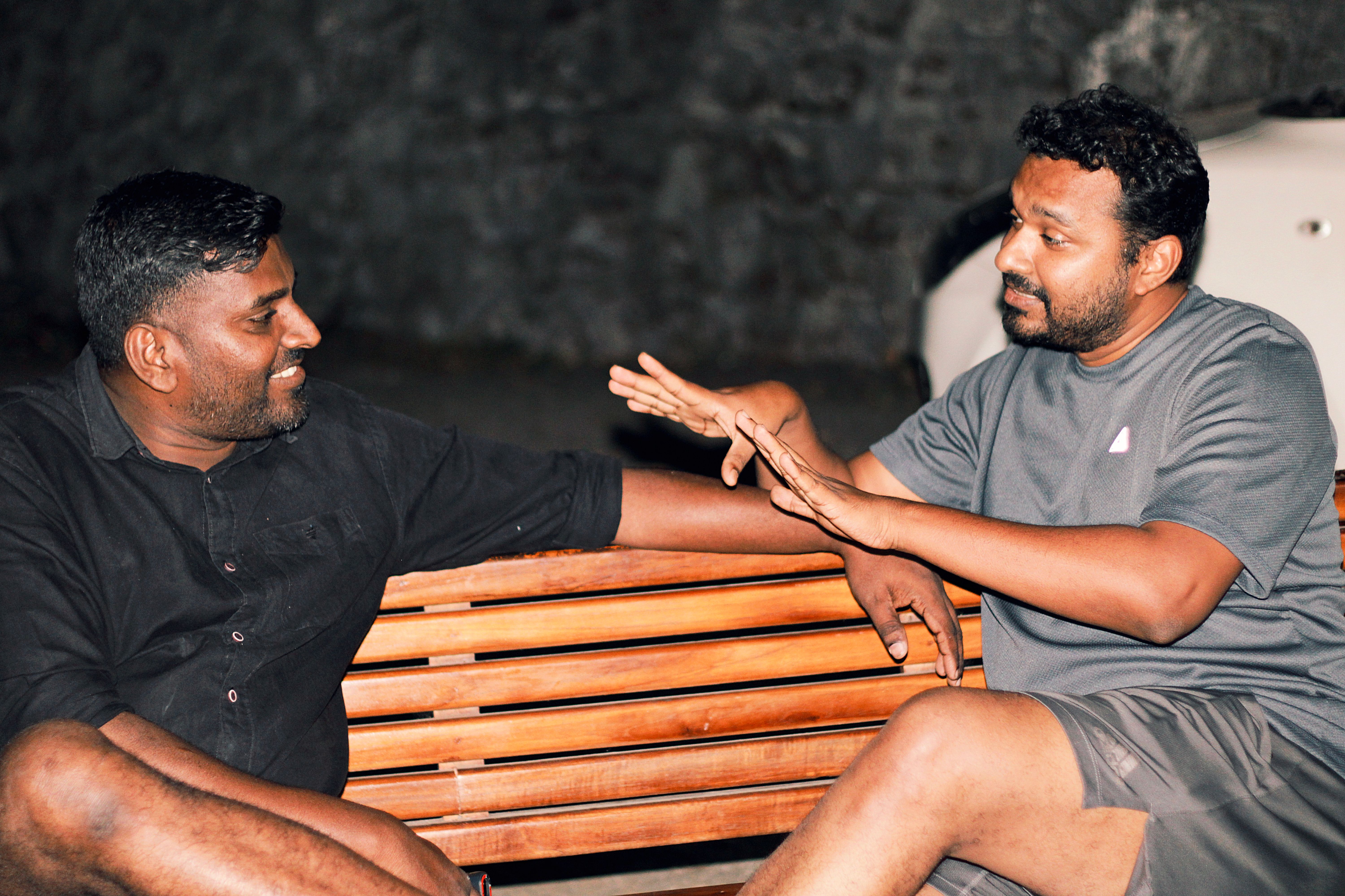 Two Men Enjoy Casual Conversation on Bench at Night · Free Stock Photo
