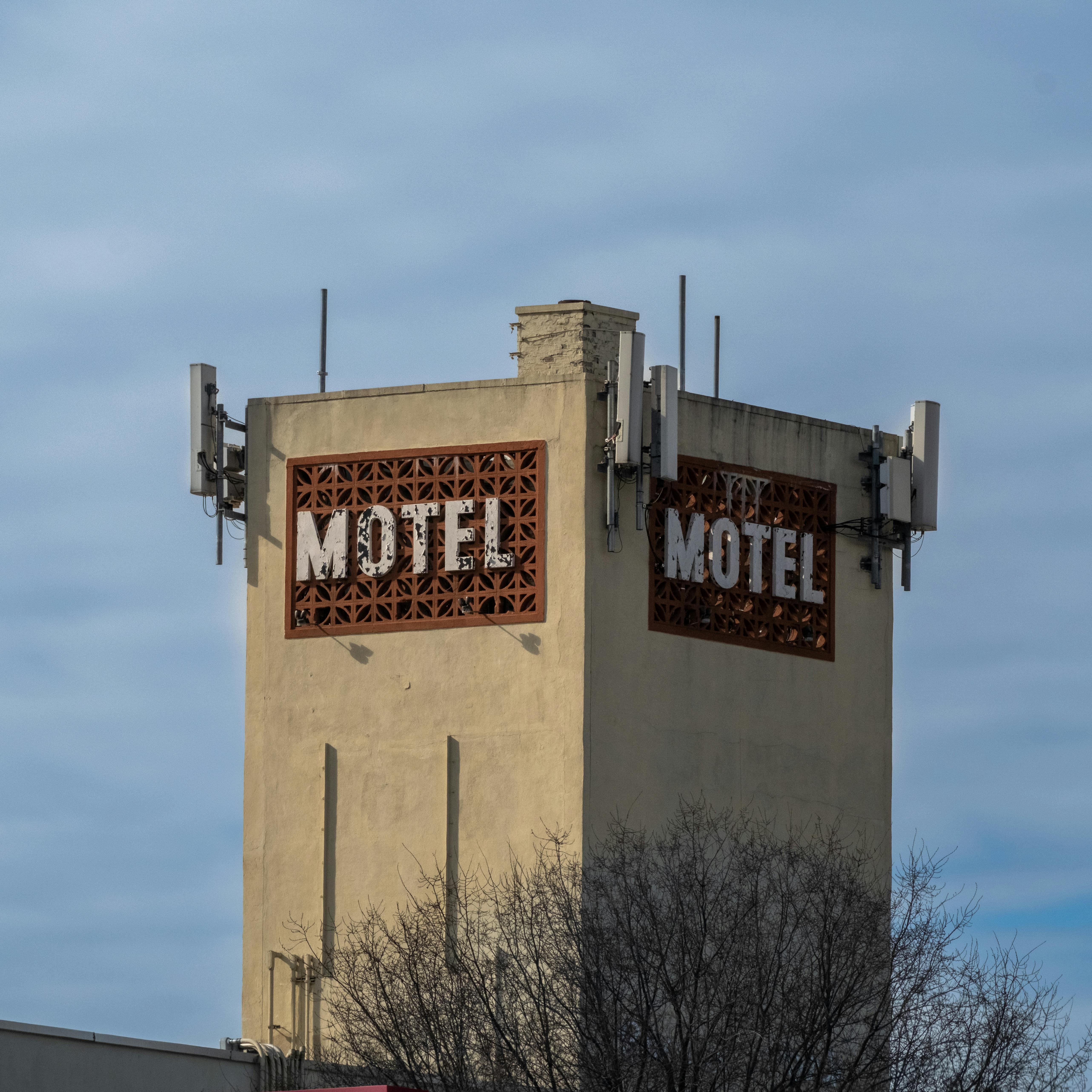 Retro Motel Sign with Urban Architecture · Free Stock Photo