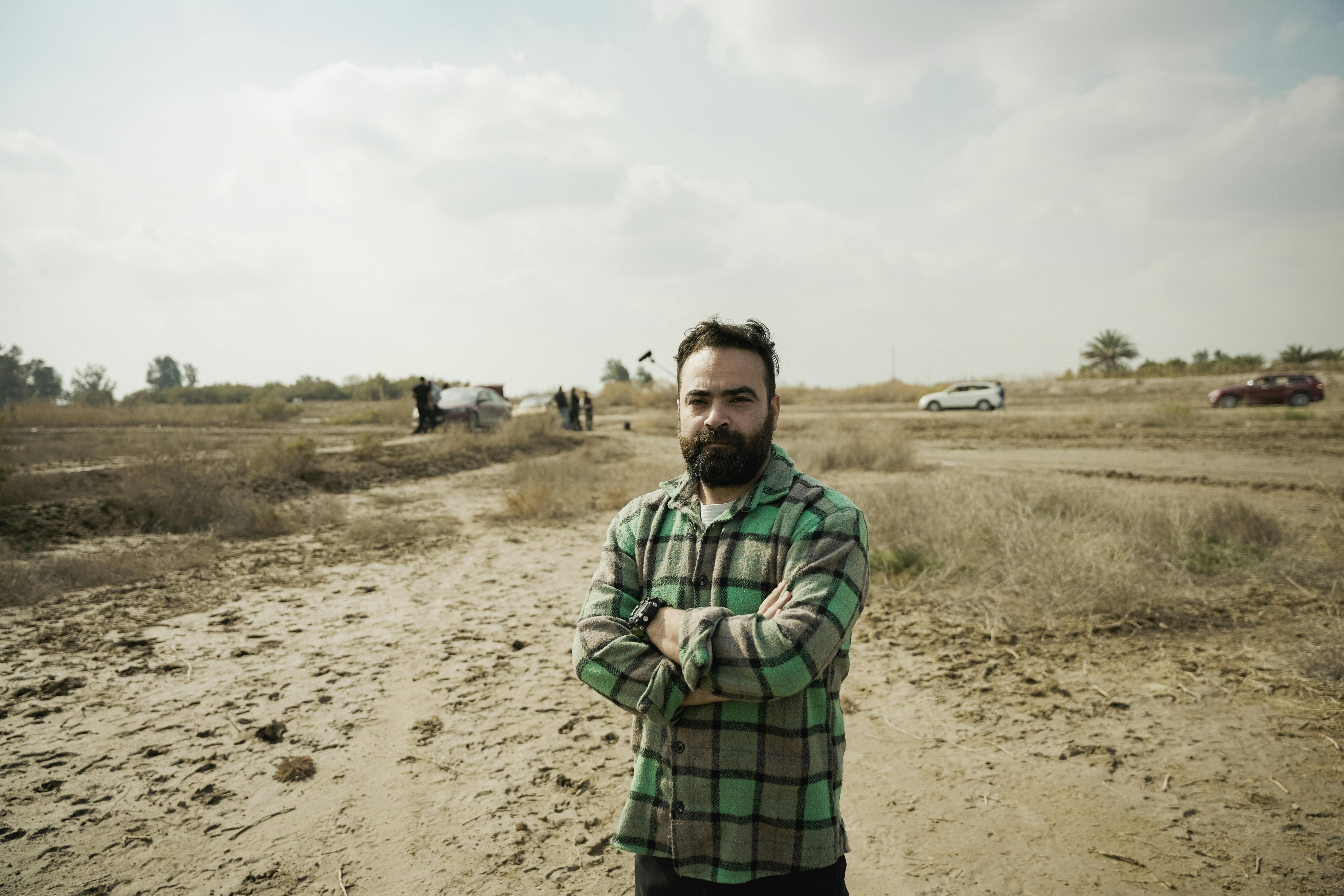 Man Standing in a Rural Landscape with Vehicles · Free Stock Photo