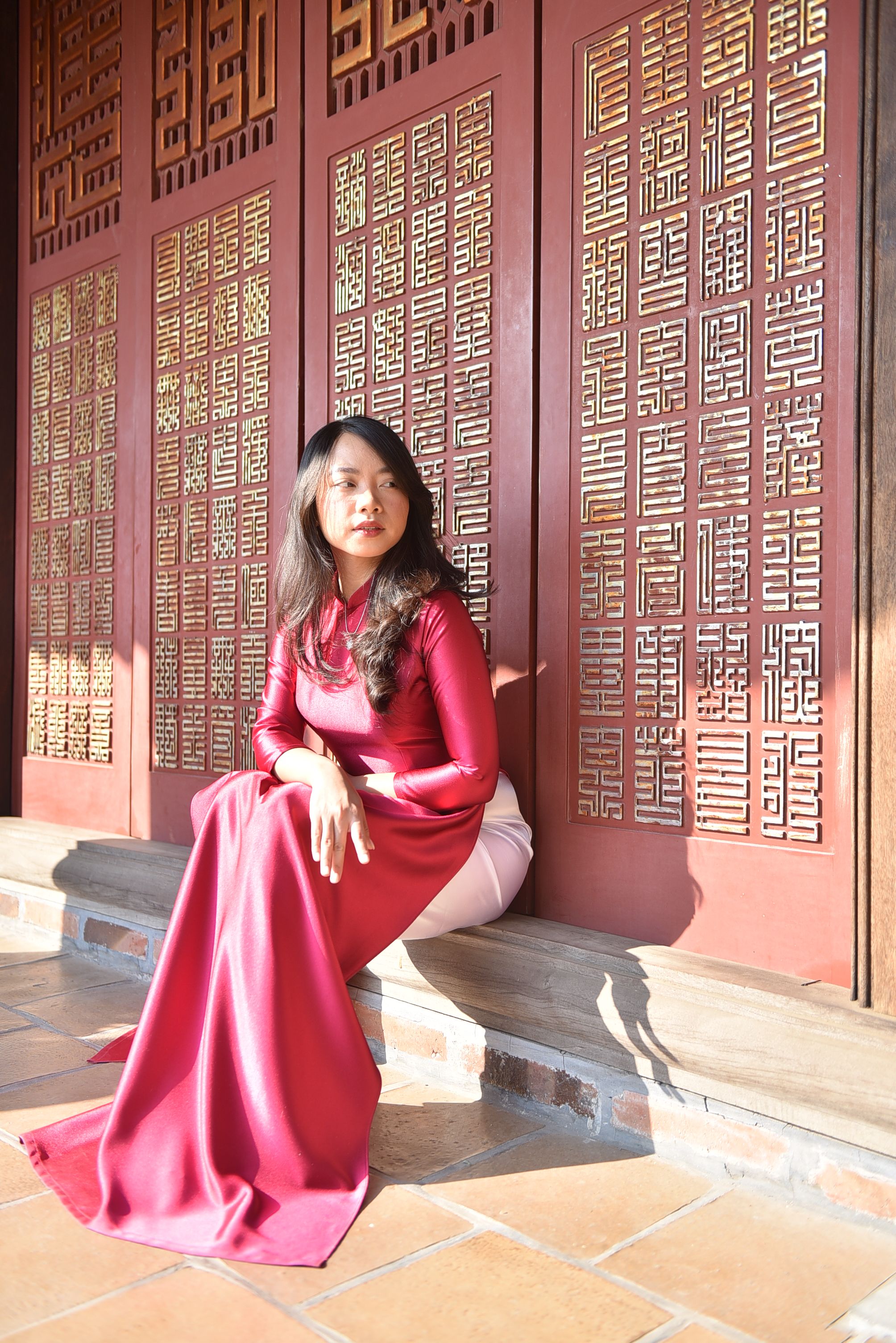 Woman in Traditional Vietnamese Dress Sitting by Ornate Doors · Free ...
