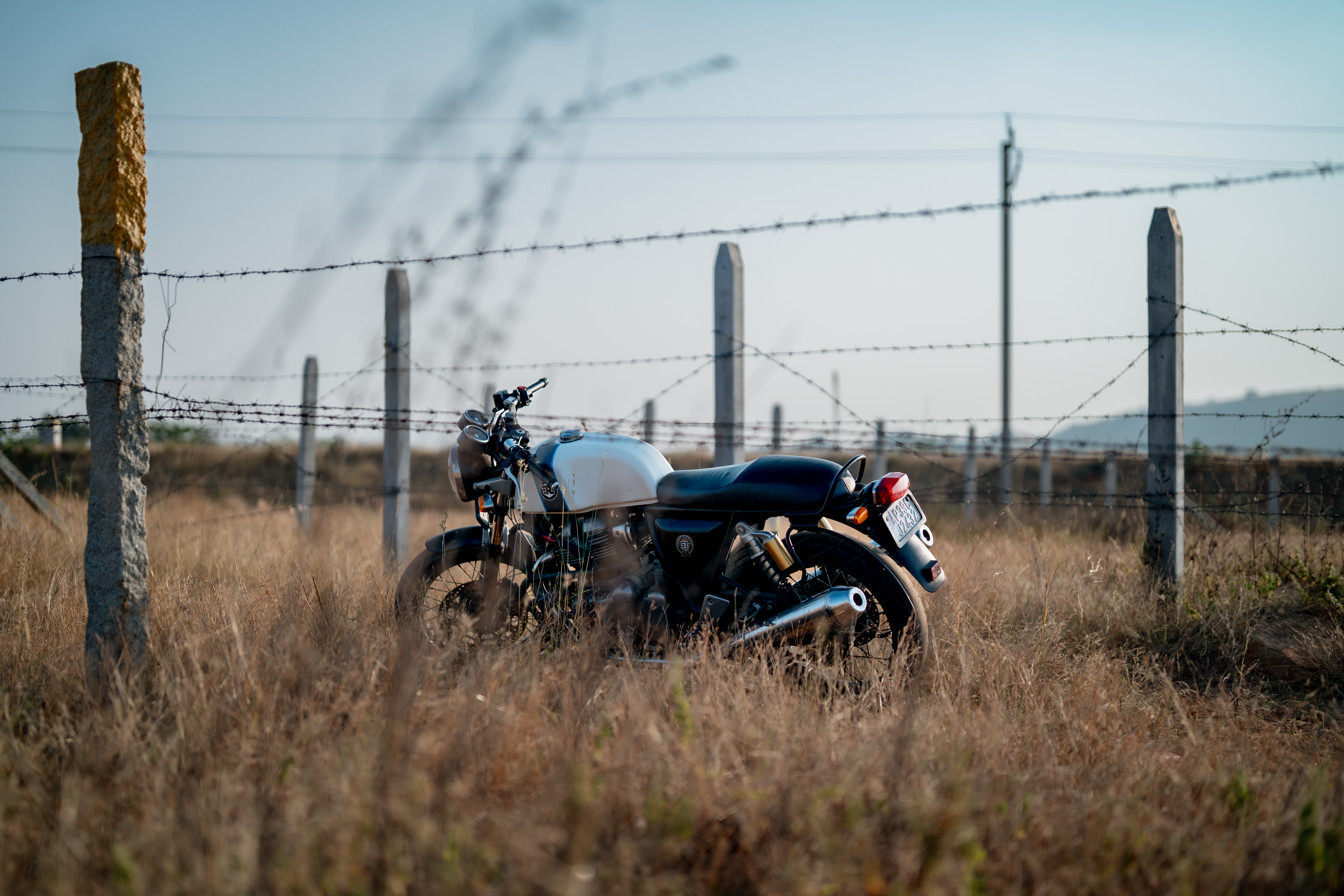 Motorcycle in Rural Indian Field with Barbed Wire Fence · Free Stock Photo