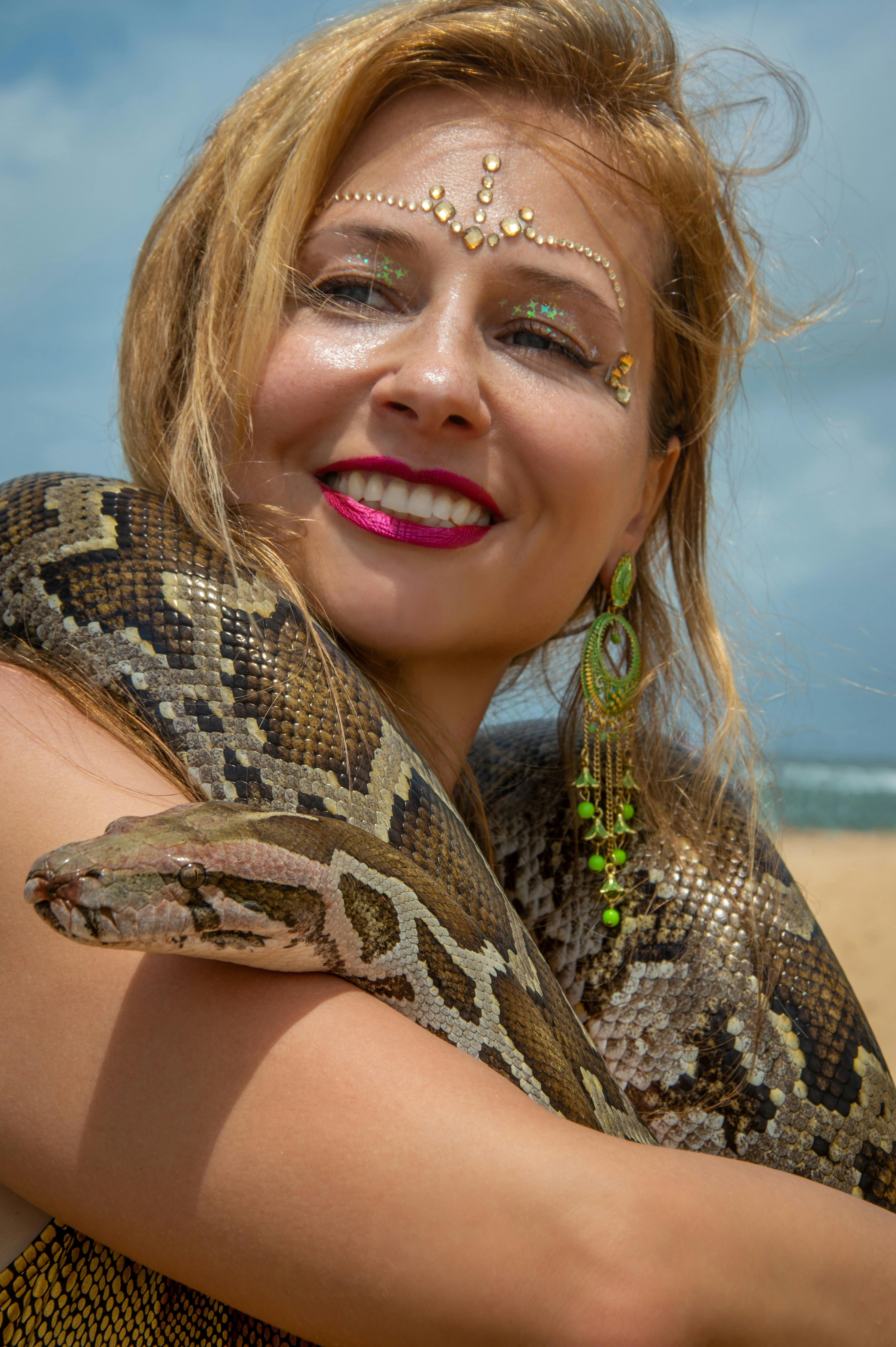 Woman Embracing Python on Beach · Free Stock Photo