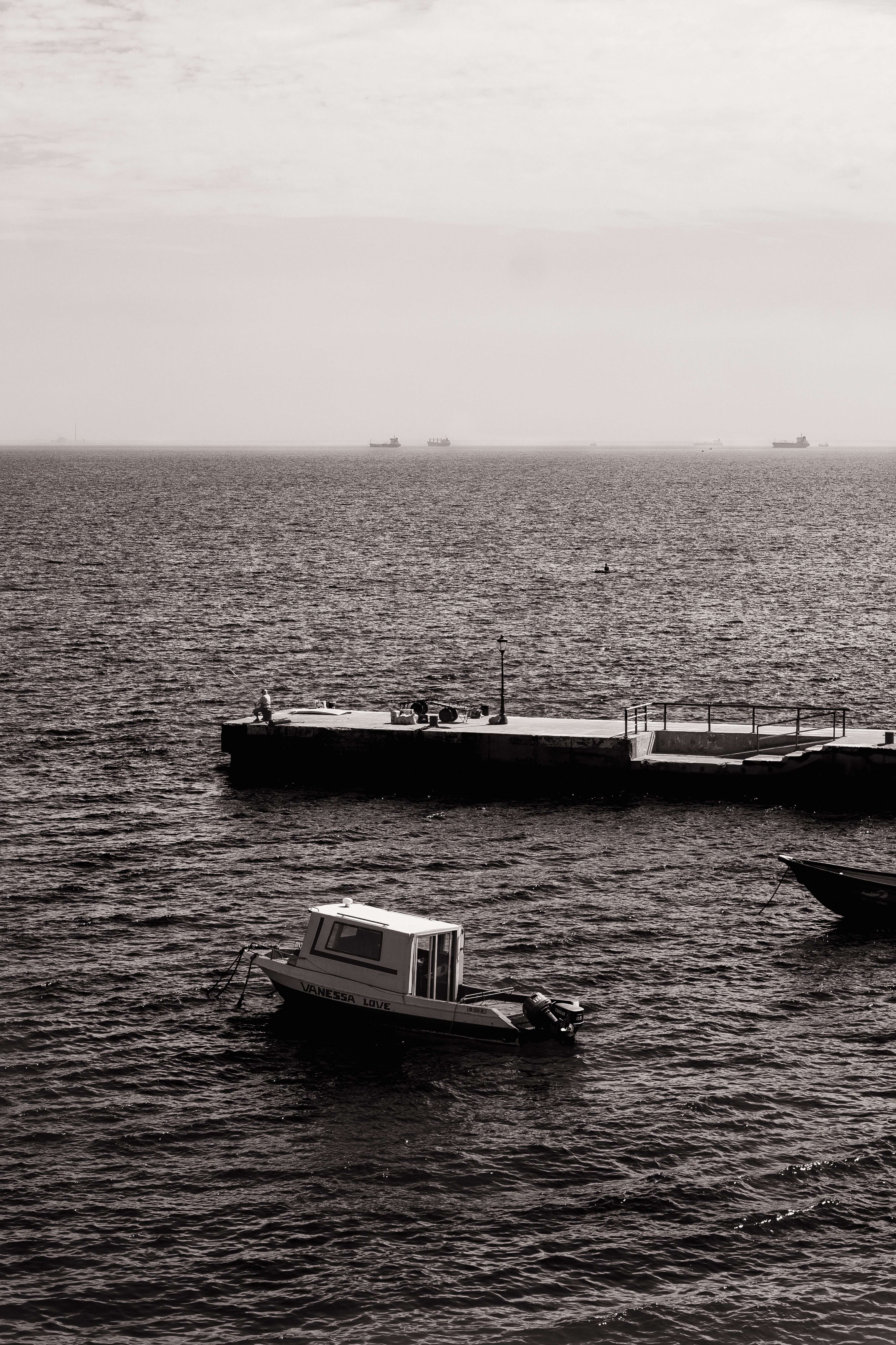 Serene Monochrome Seascape with Boat and Pier · Free Stock Photo