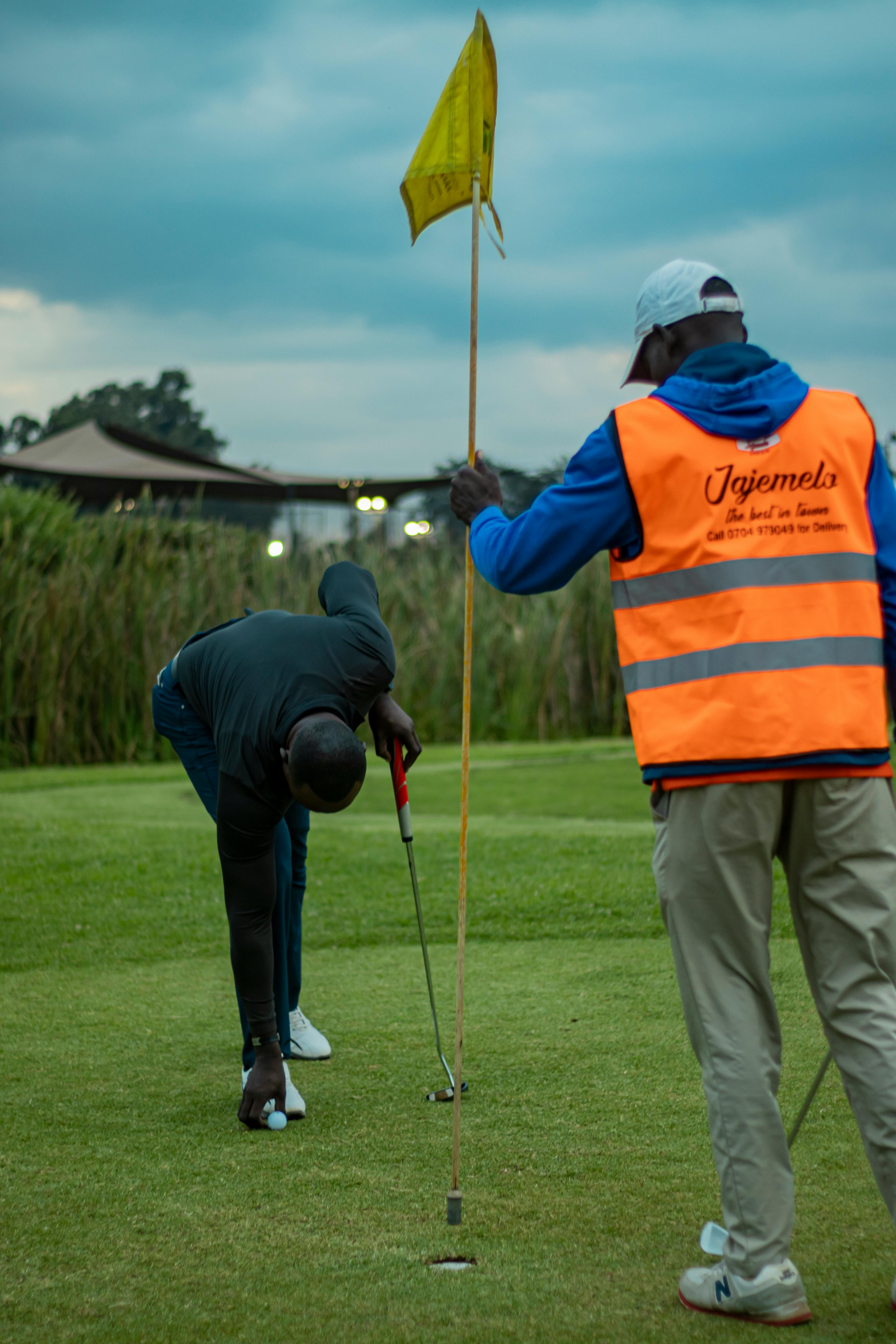Golf Caddy Assisting Player at Nairobi Course · Free Stock Photo