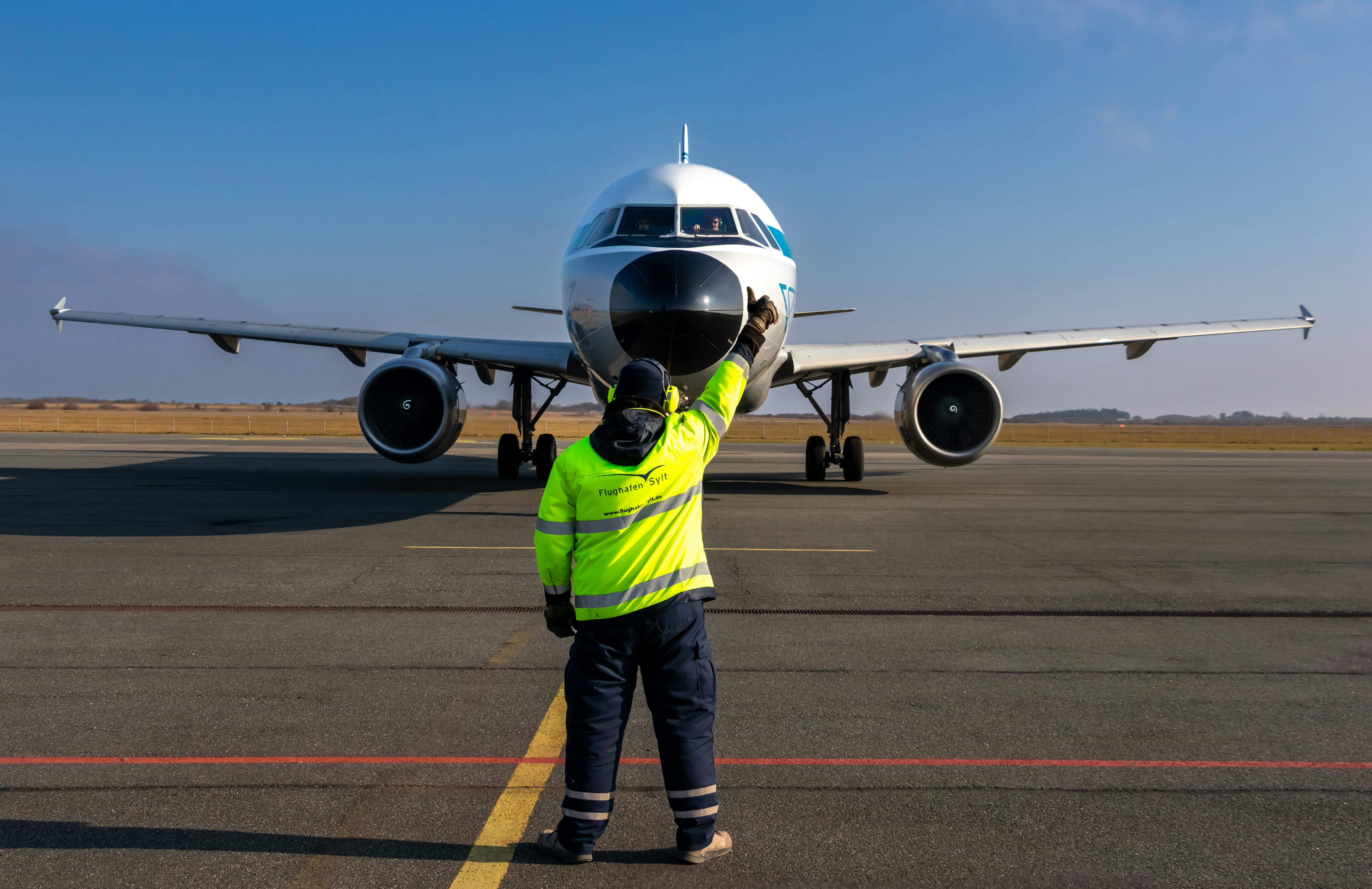 Airport Worker Guiding Airplane on Runway · Free Stock Photo