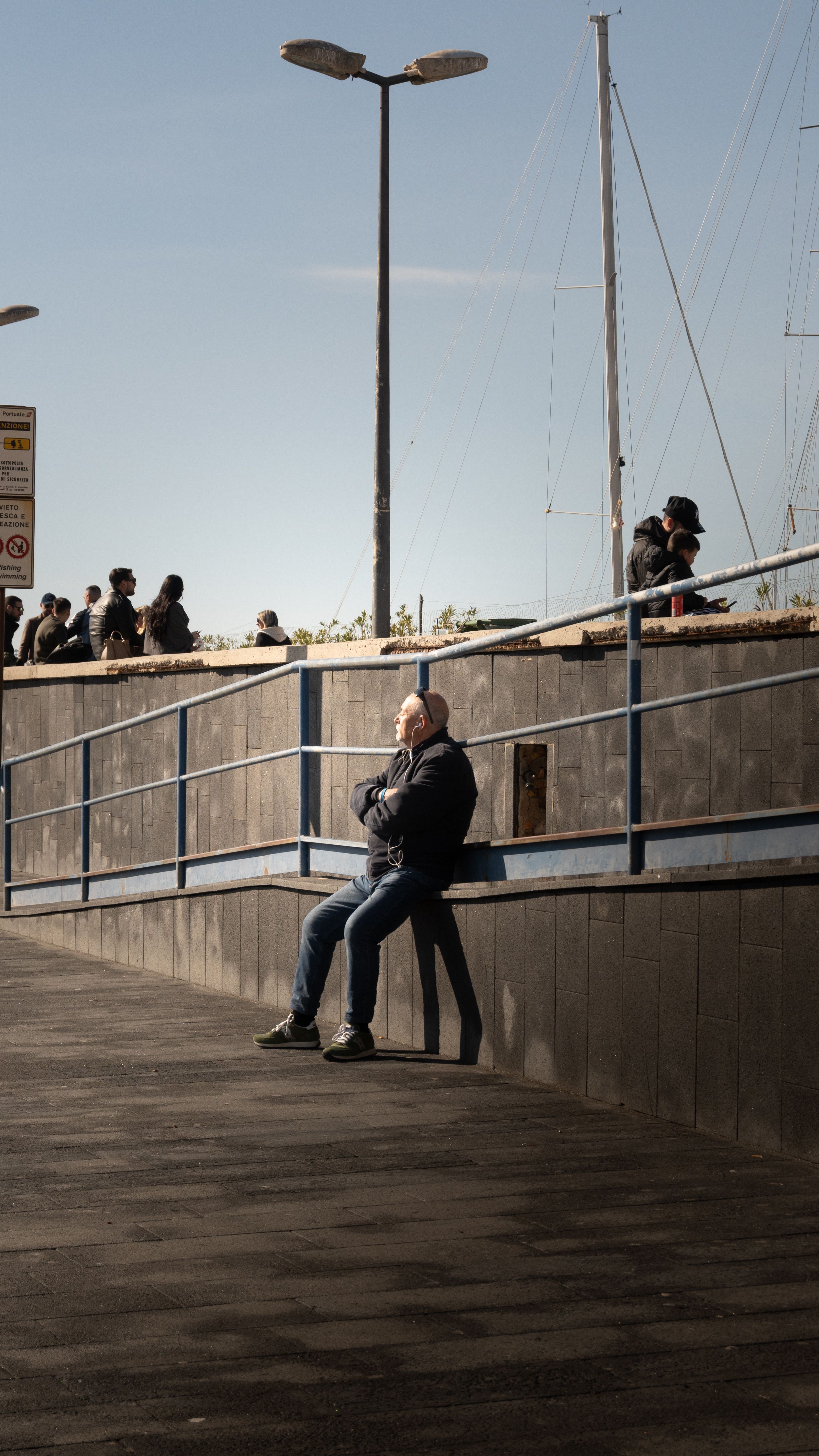 Man Sitting on Urban Wall Under Street Lamp · Free Stock Photo