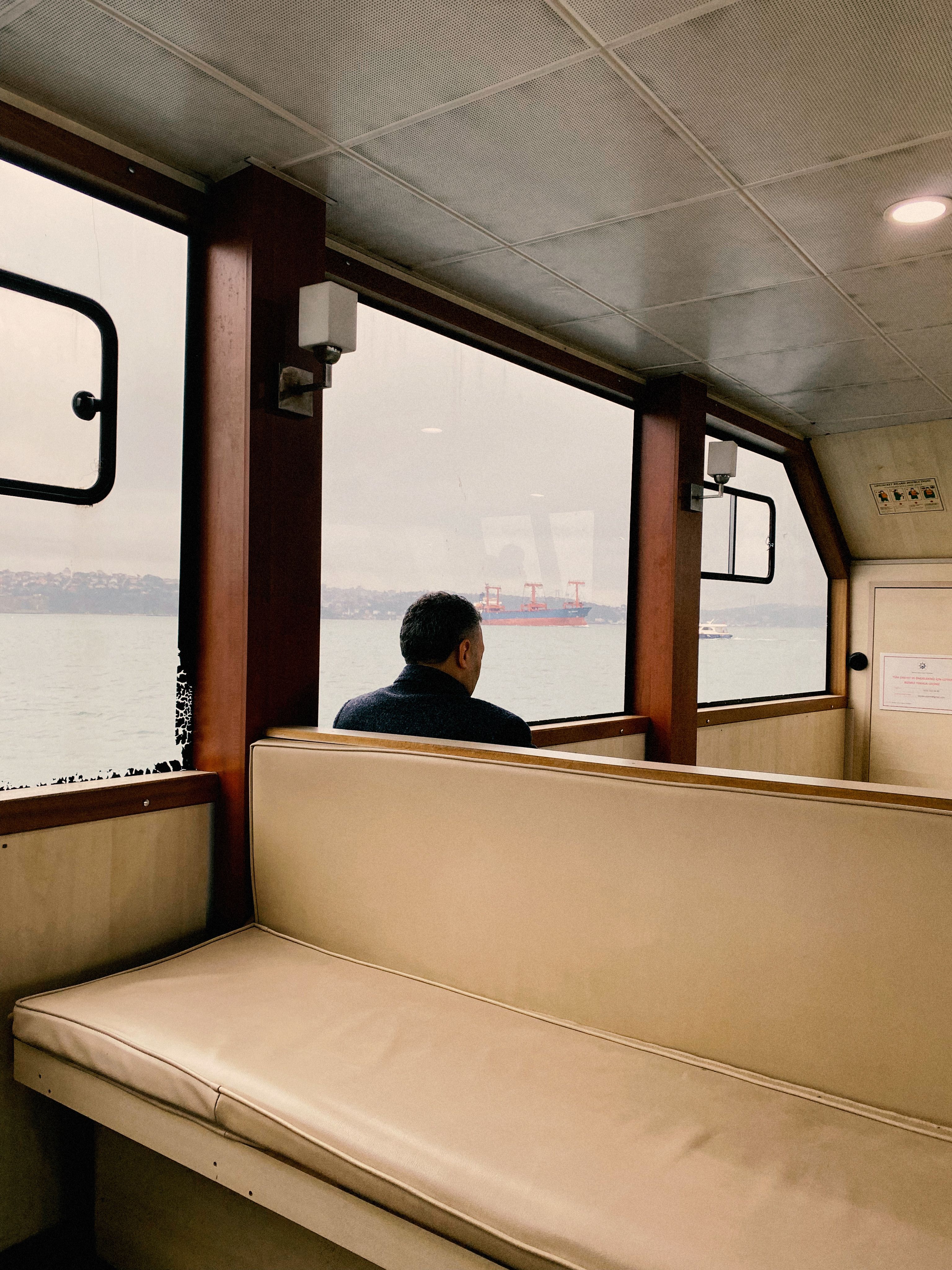 Man on Ferry Overlooking Waterfront Scene · Free Stock Photo