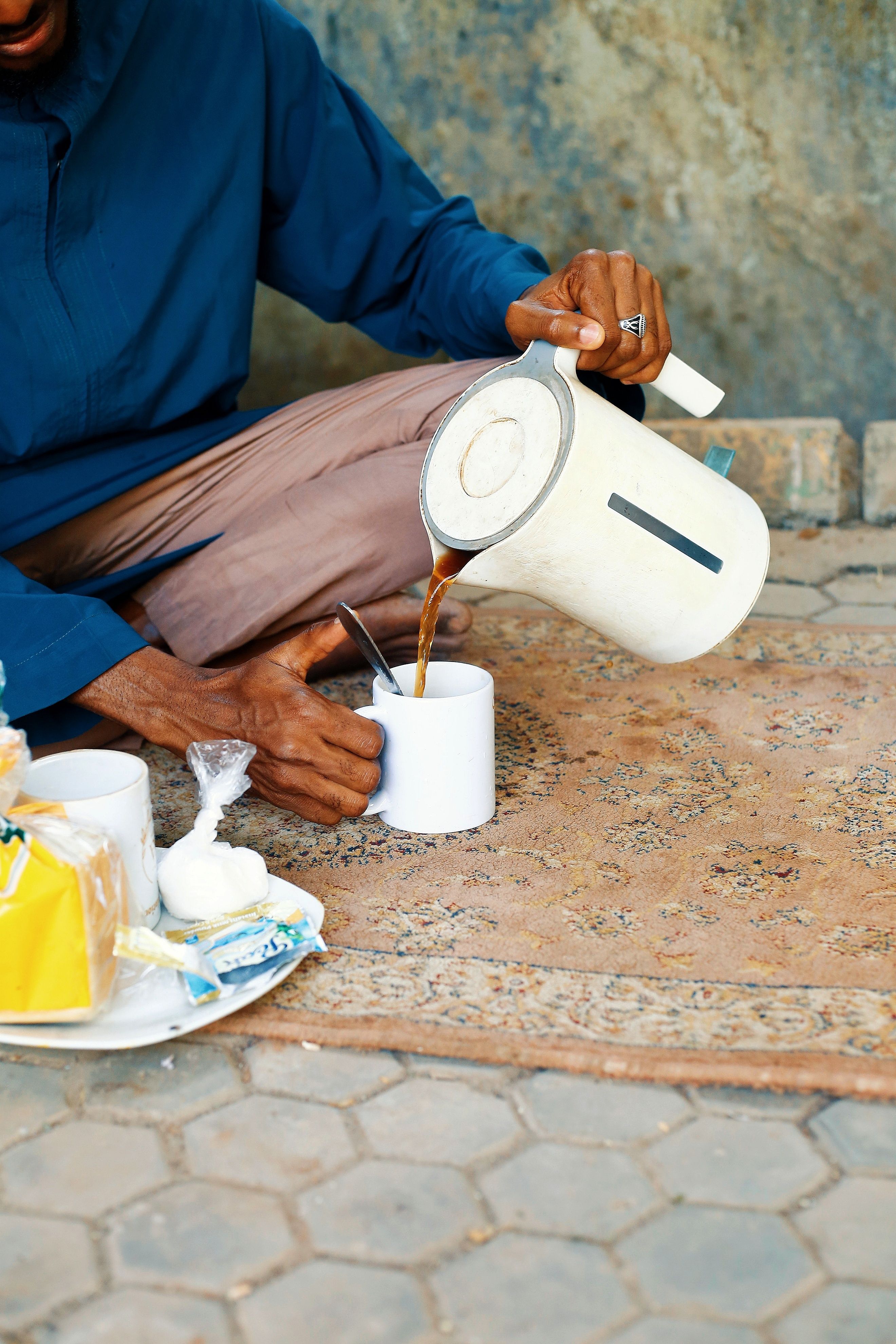 Nigerian Man Pouring Tea on Outdoor Rug · Free Stock Photo