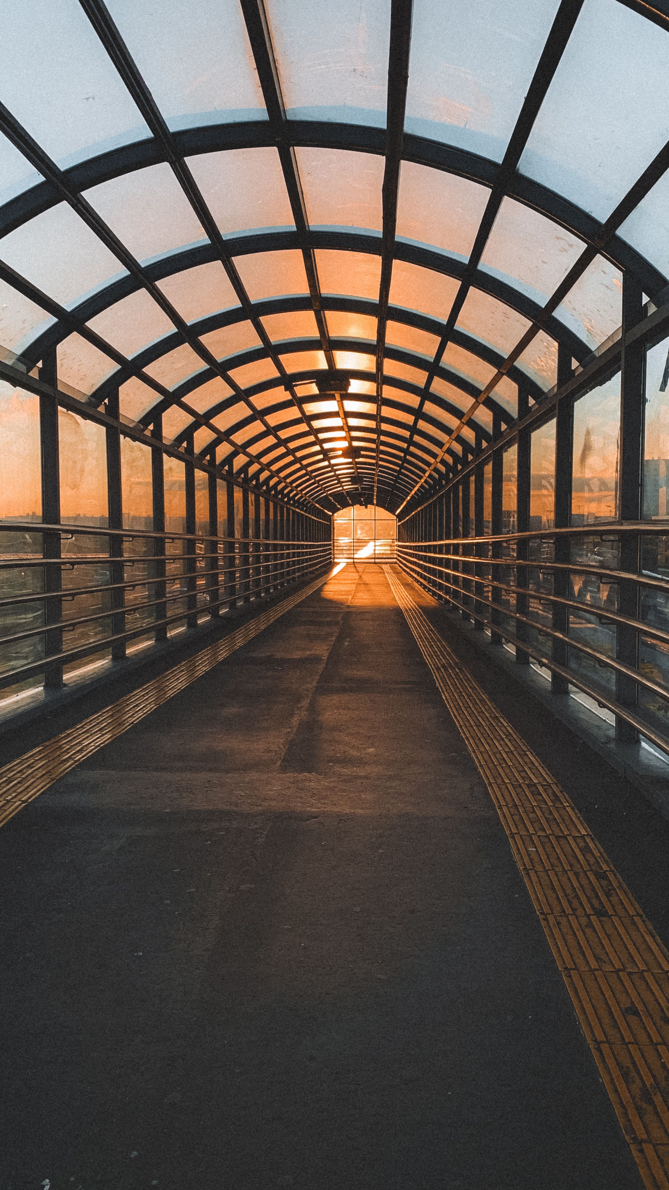 Dramatic Sunset View Through Glass Pedestrian Tunnel · Free Stock Photo