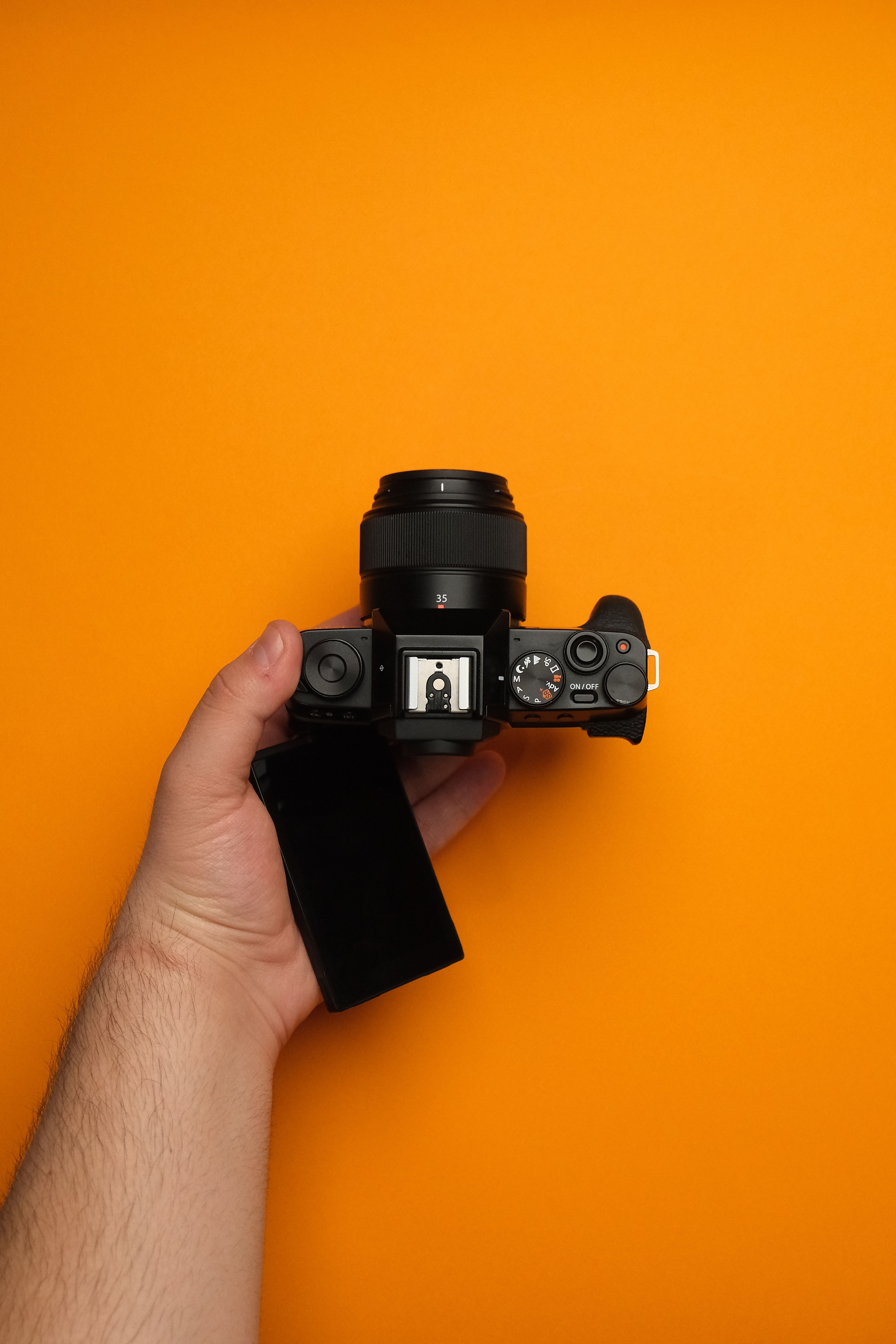 Top View of Camera Held Against Orange Background · Free Stock Photo