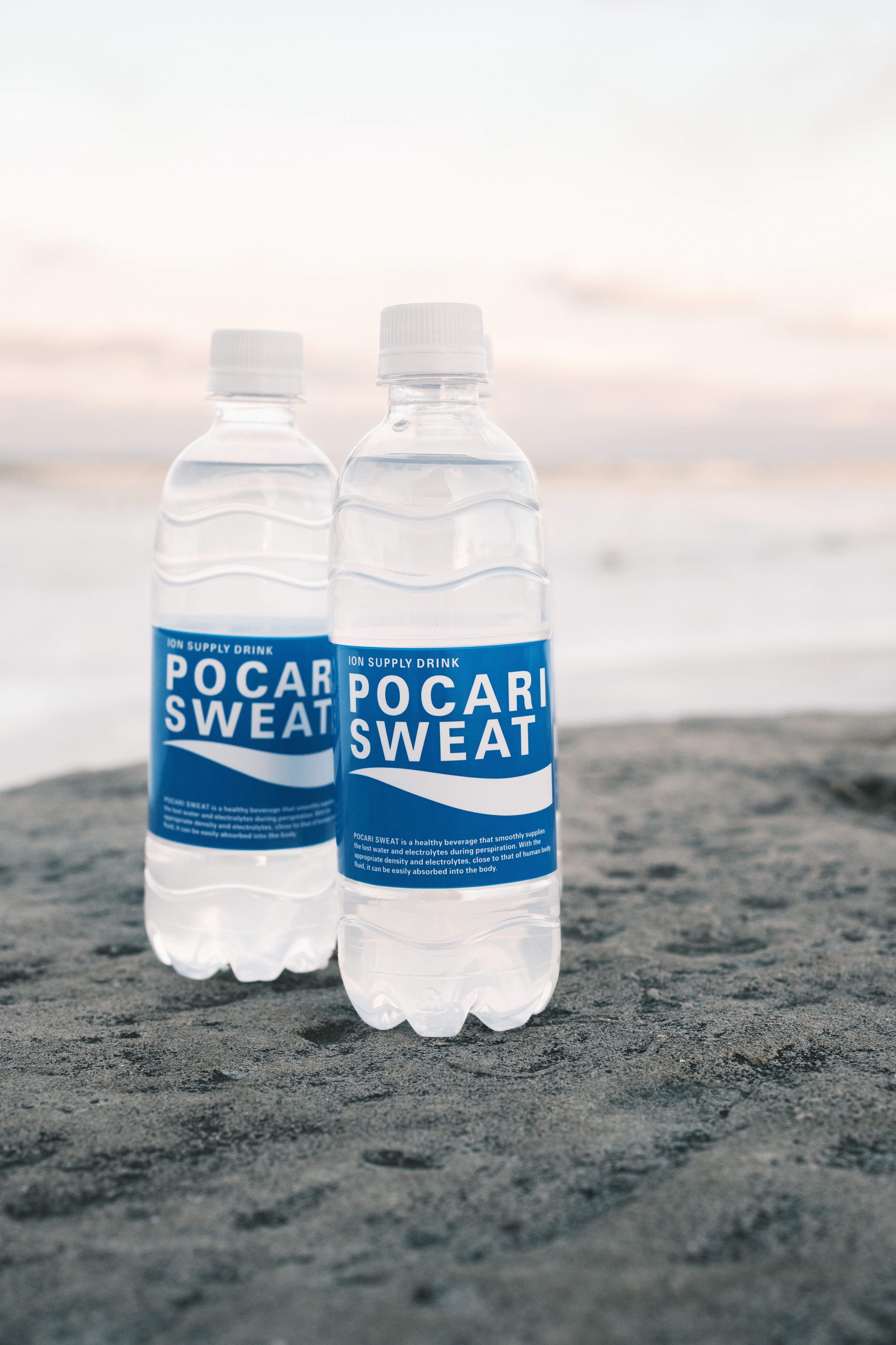Pocari Sweat Bottles on a Beach at Sunset · Free Stock Photo