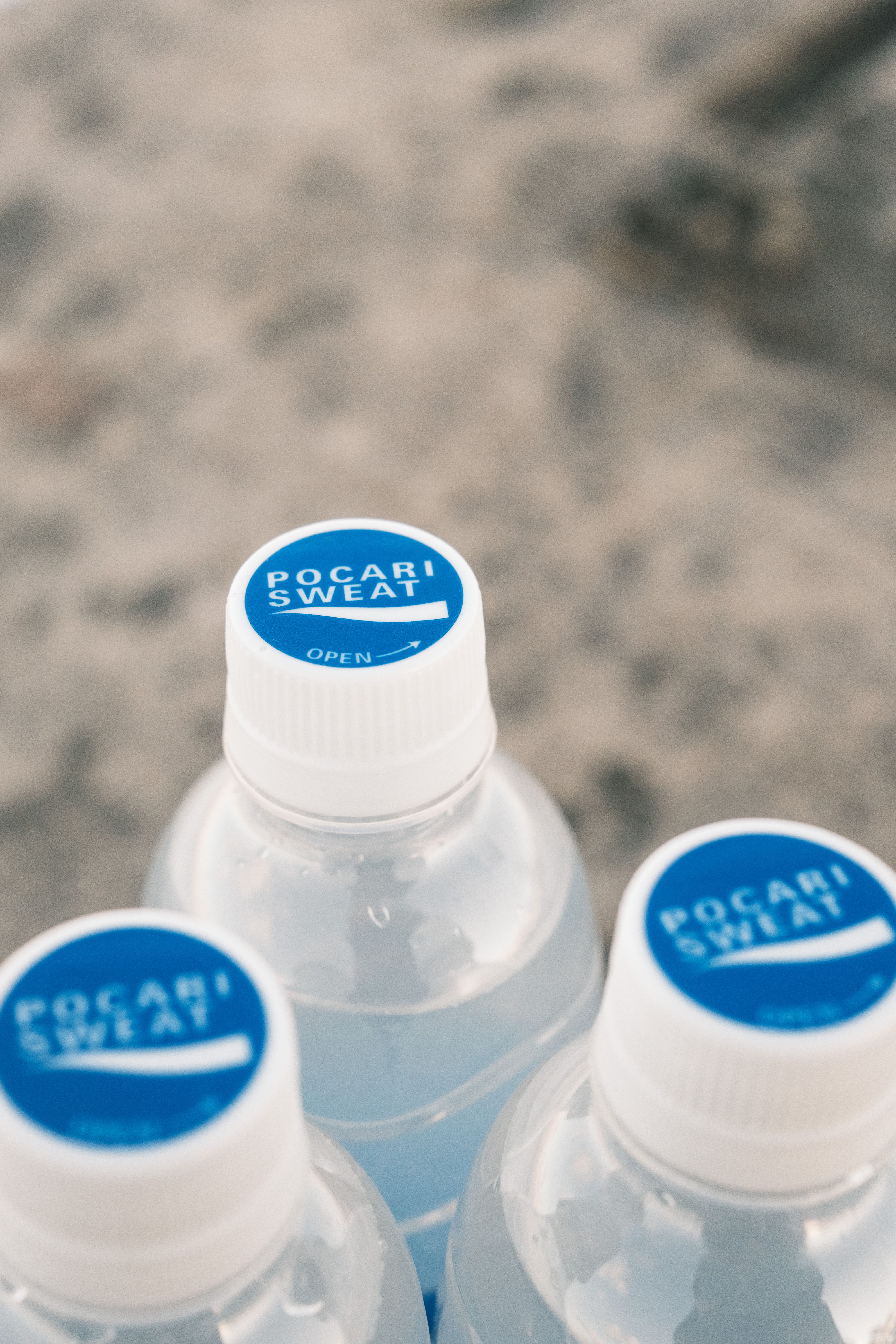 Close-up of Pocari Sweat Bottles on Sand · Free Stock Photo