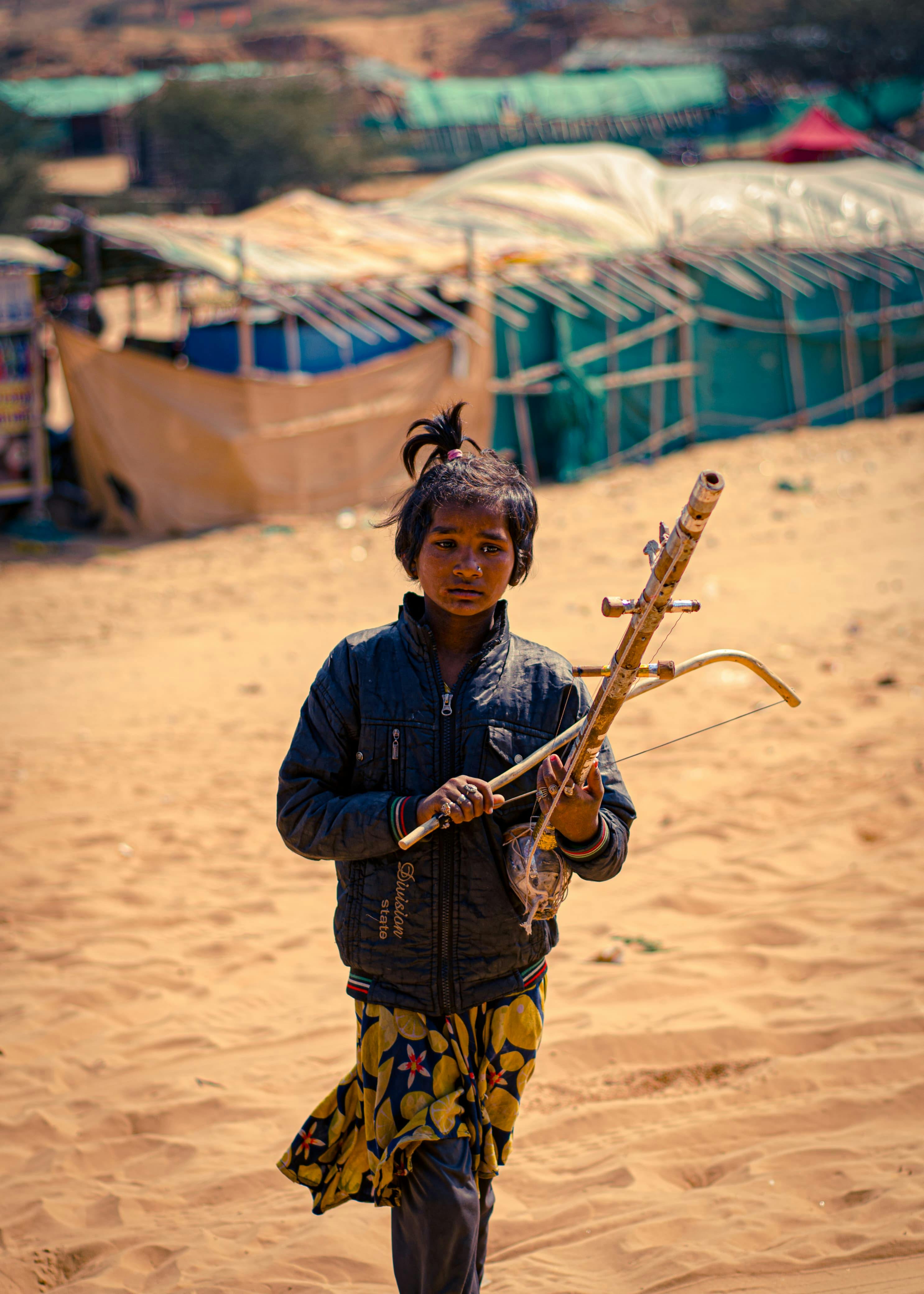 Young Boy with Traditional Musical Instrument in Desert · Free Stock Photo