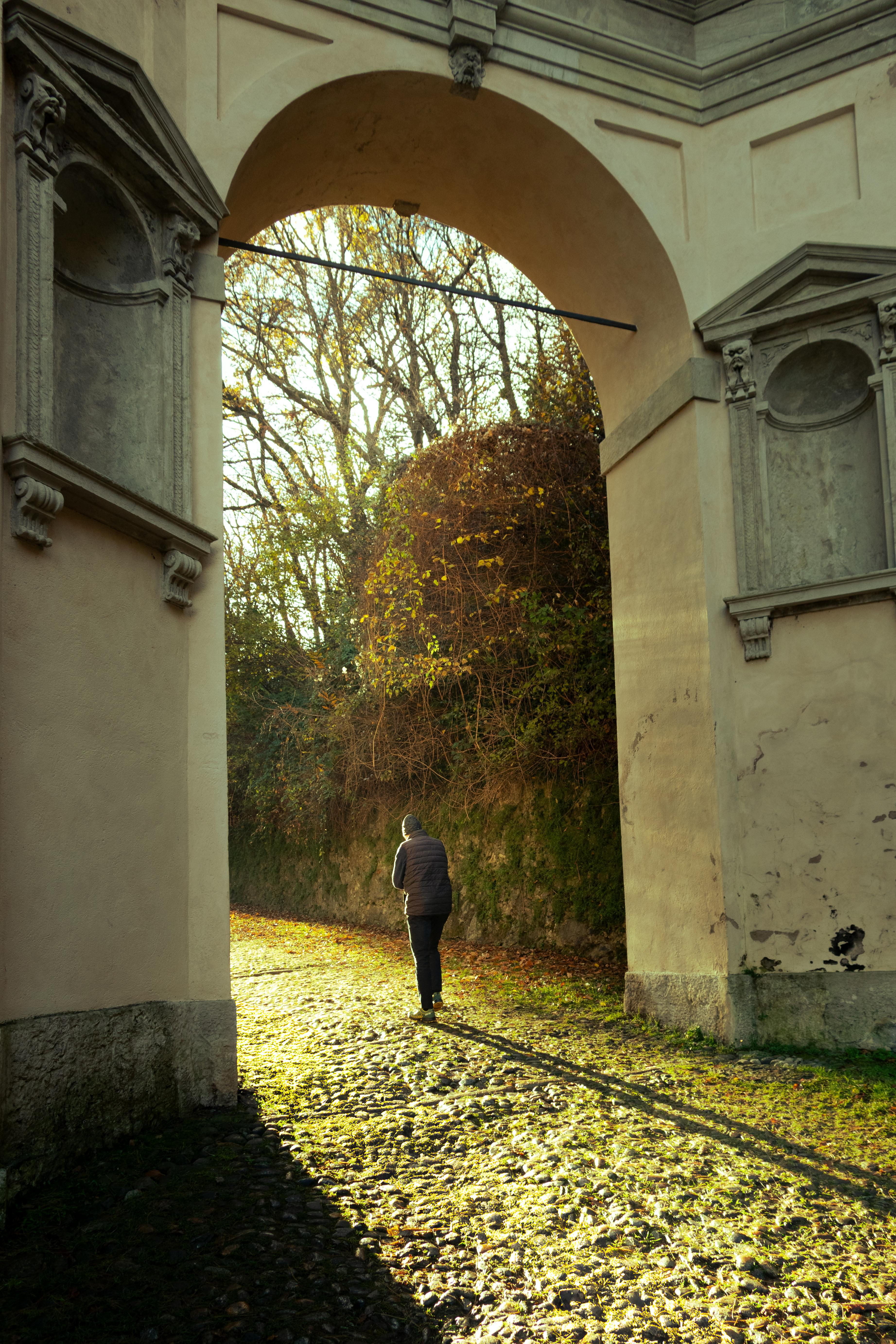 Solitary Walk through Sunlit Stone Archway · Free Stock Photo