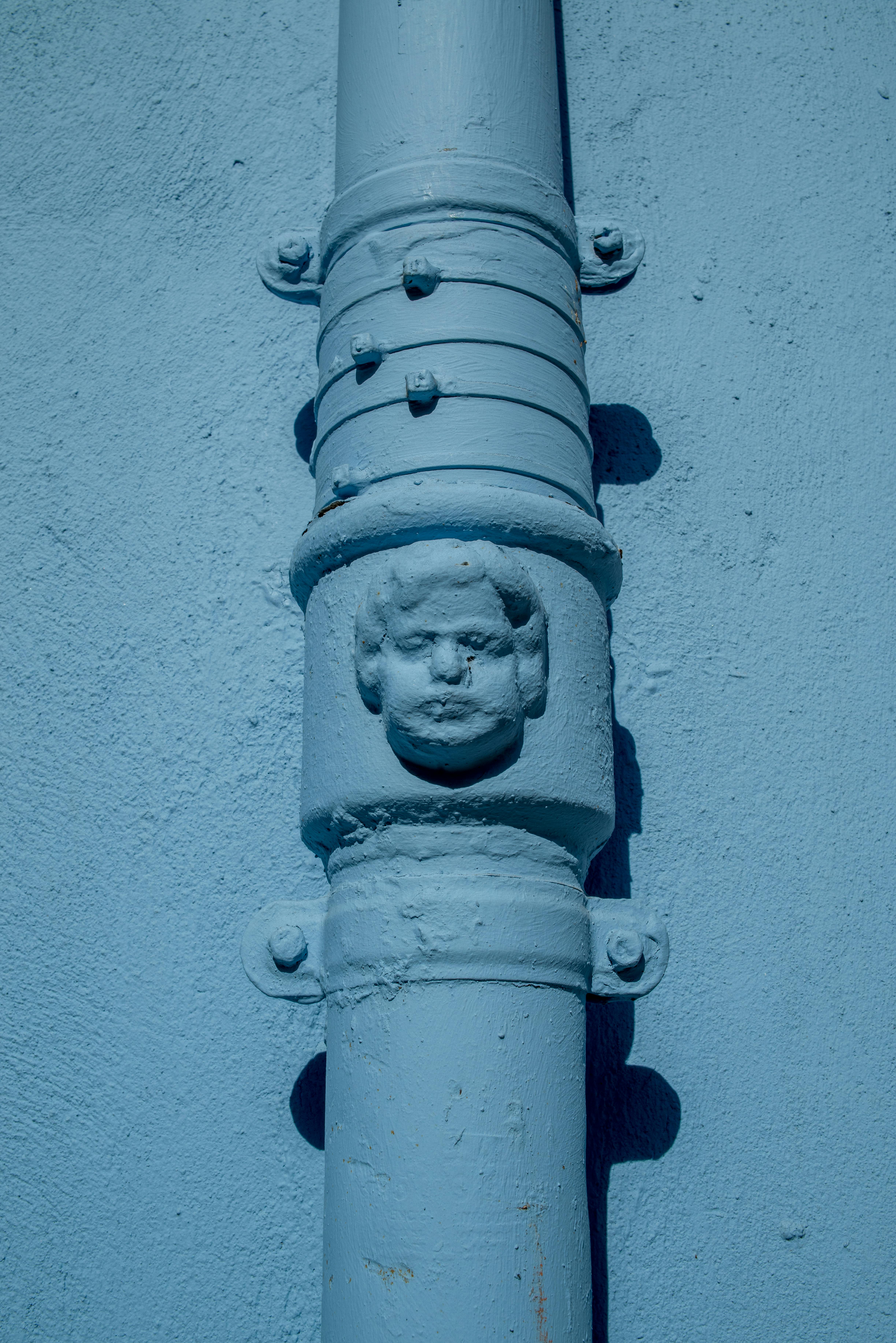 Blue Pipe with Embossed Face on Wall · Free Stock Photo