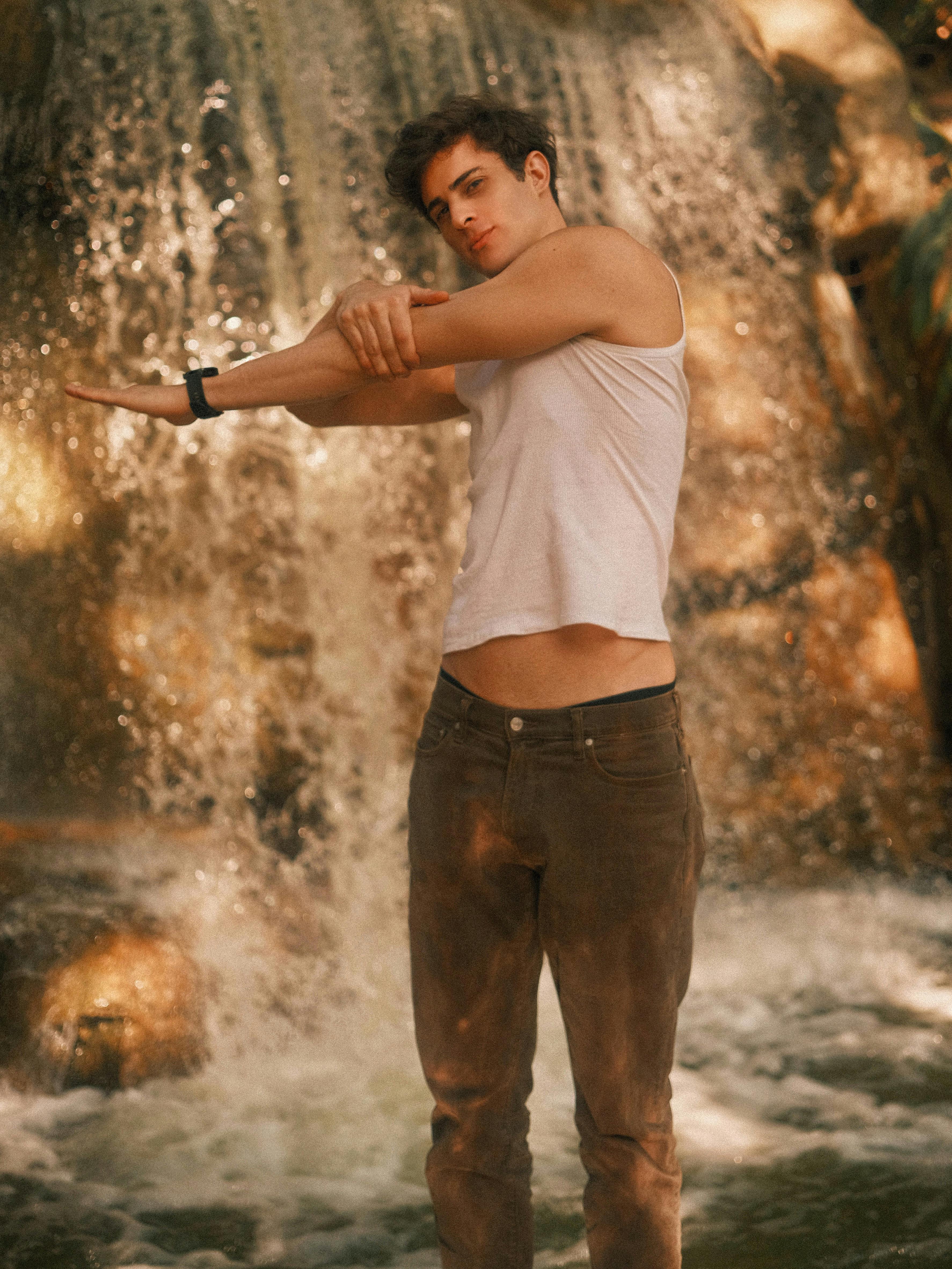Young Man Stretching by a Waterfall in Nature · Free Stock Photo