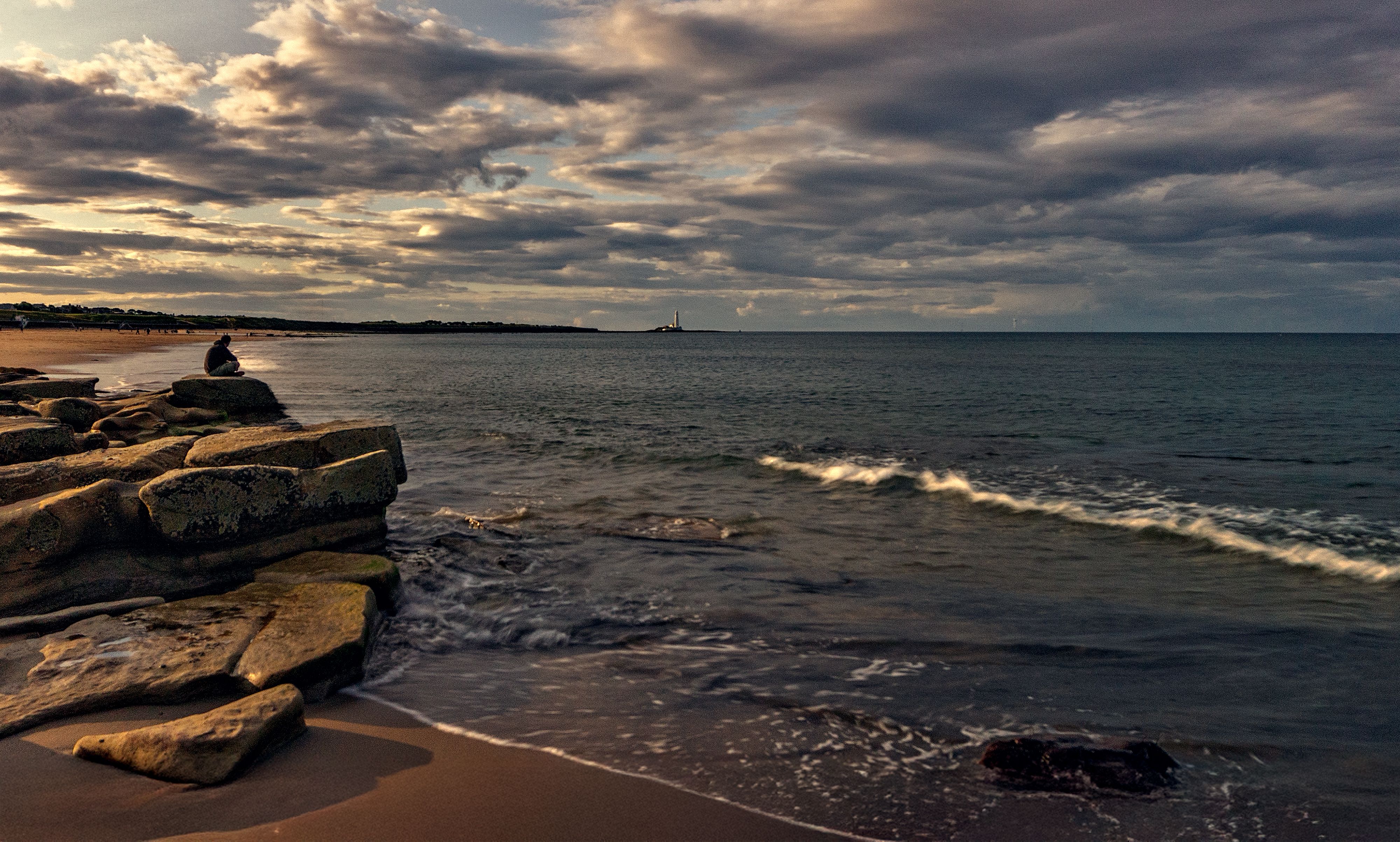 Serene Beach at Twilight with Distant Lighthouse · Free Stock Photo